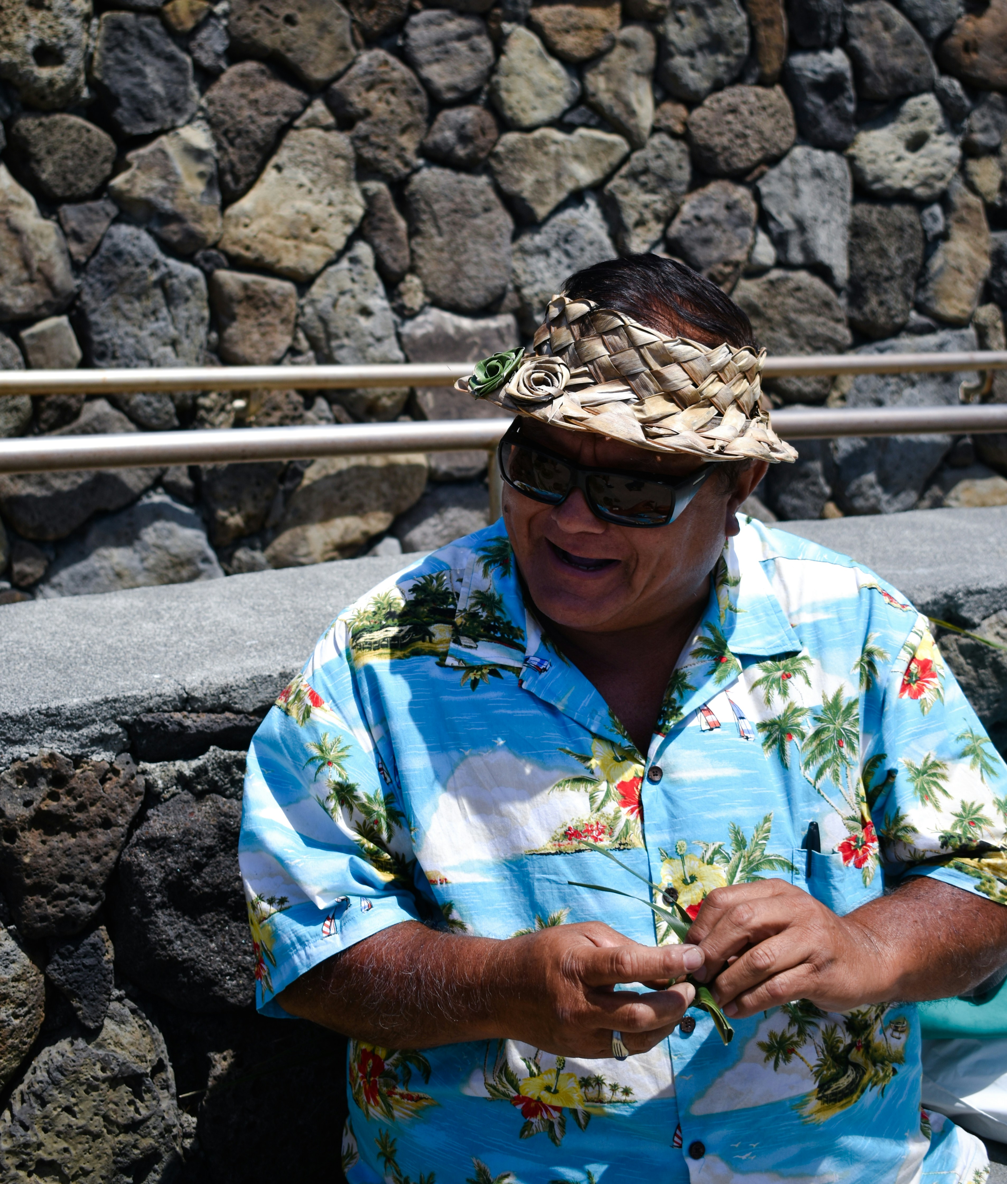Hawaiian Loupe: A relaxed vendor in a tropical shirt beside a stone seawall