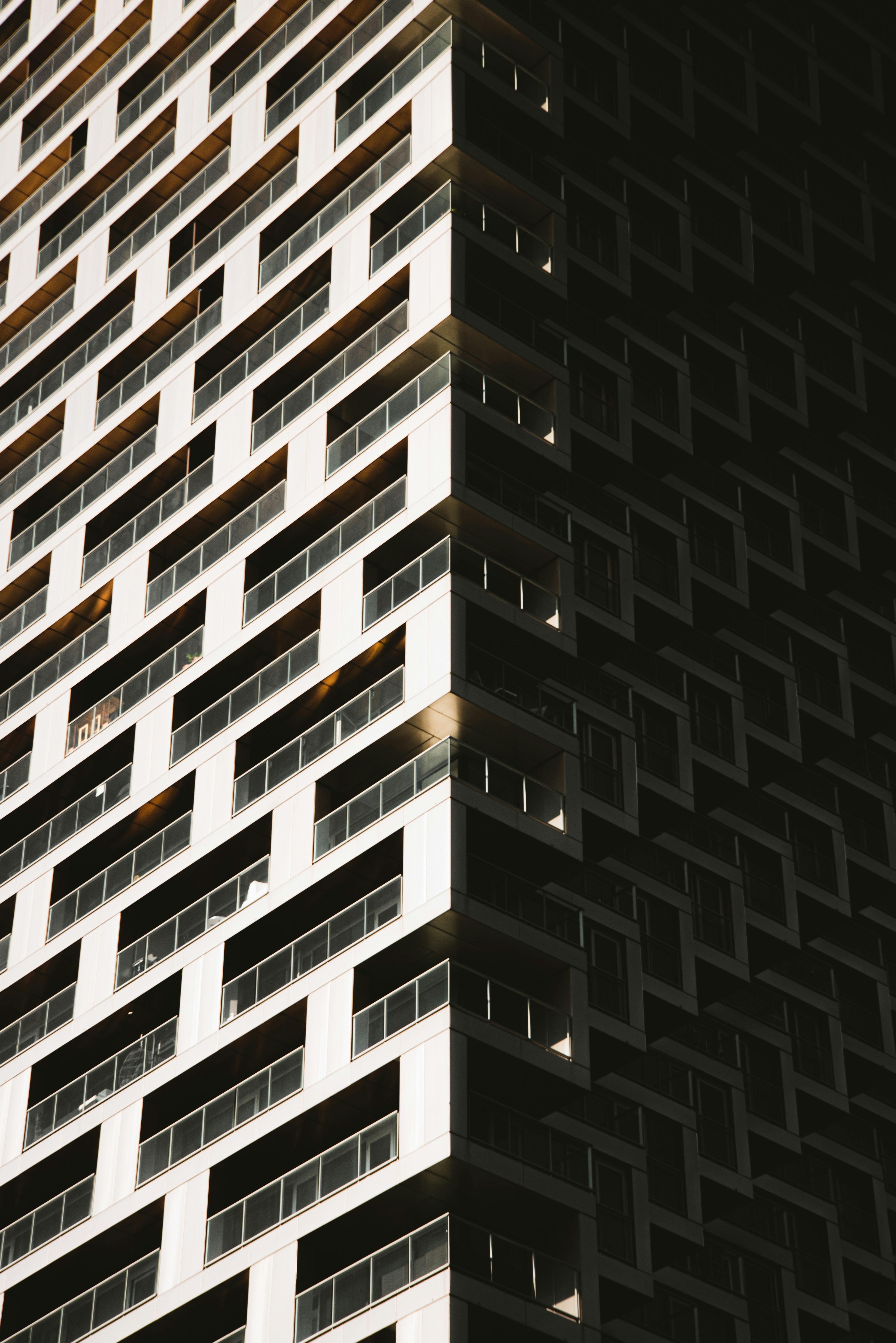 Modern high-rise building showcasing a striking contrast between light and shadow, emphasizing geometric patterns and balcony details.