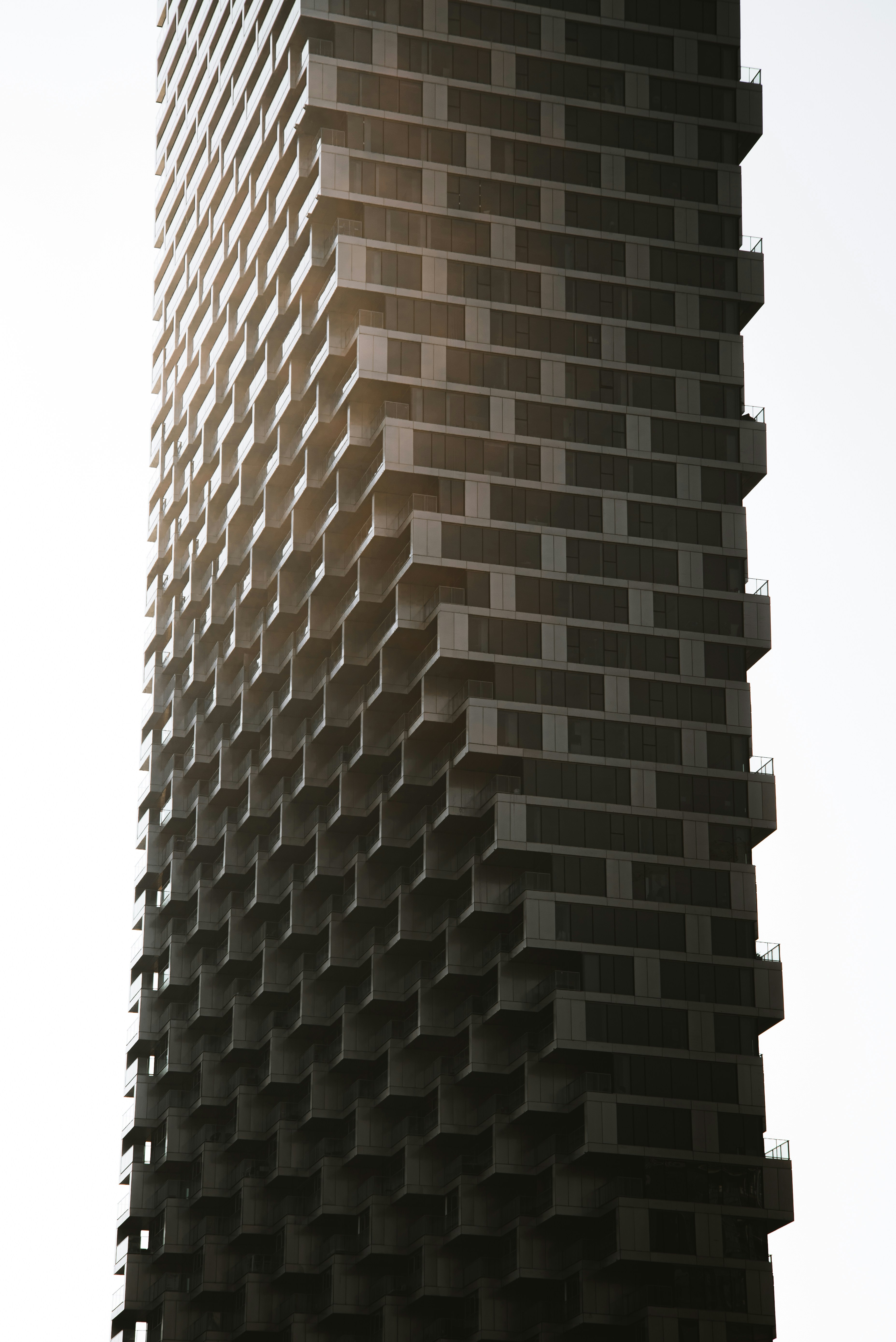 A modern high-rise building showcasing a unique façade with a grid pattern and balconies. The image captures the interplay of light and shadow on the structure.