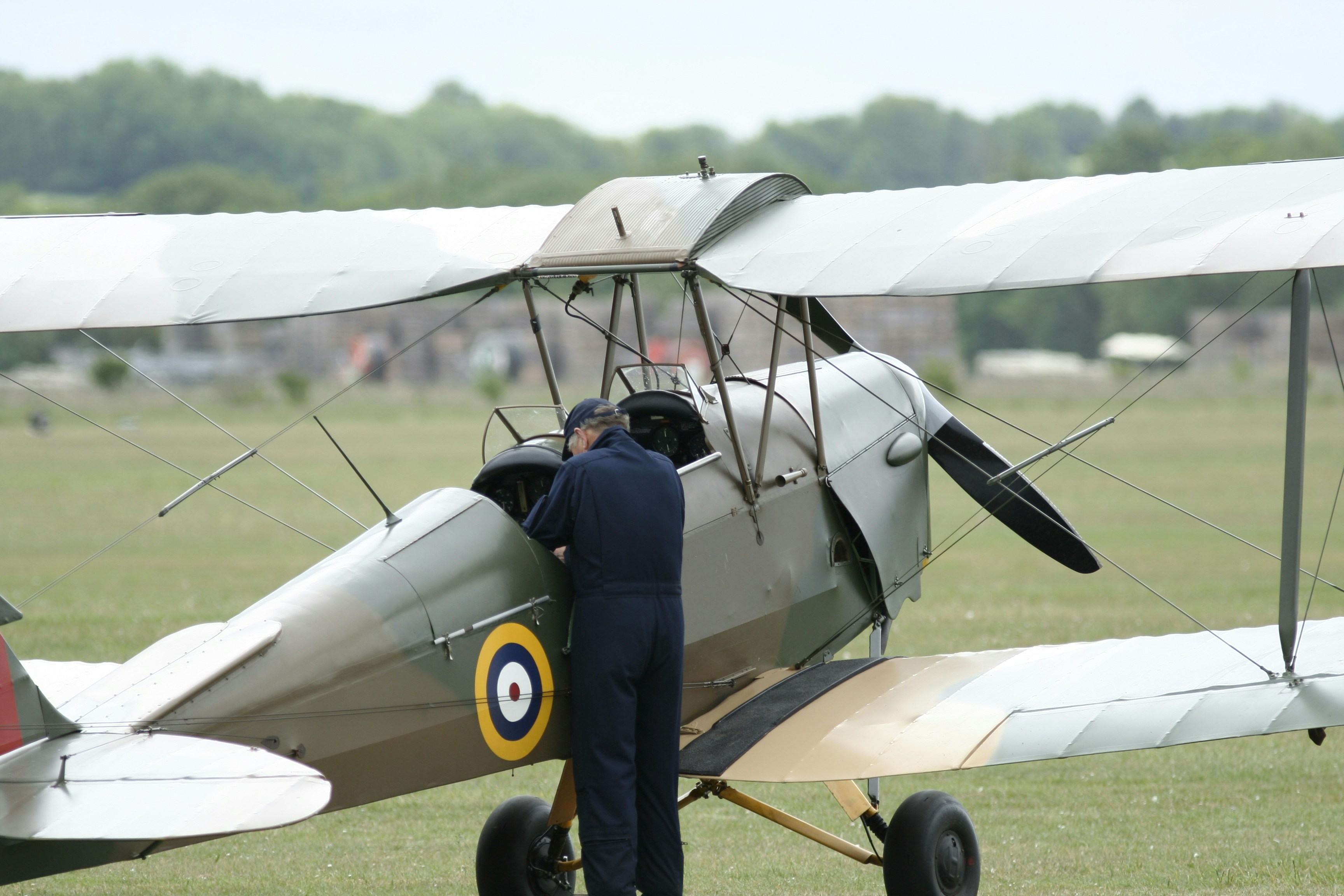 man in blue jacket and blue denim jeans standing on yellow and black plane during daytime