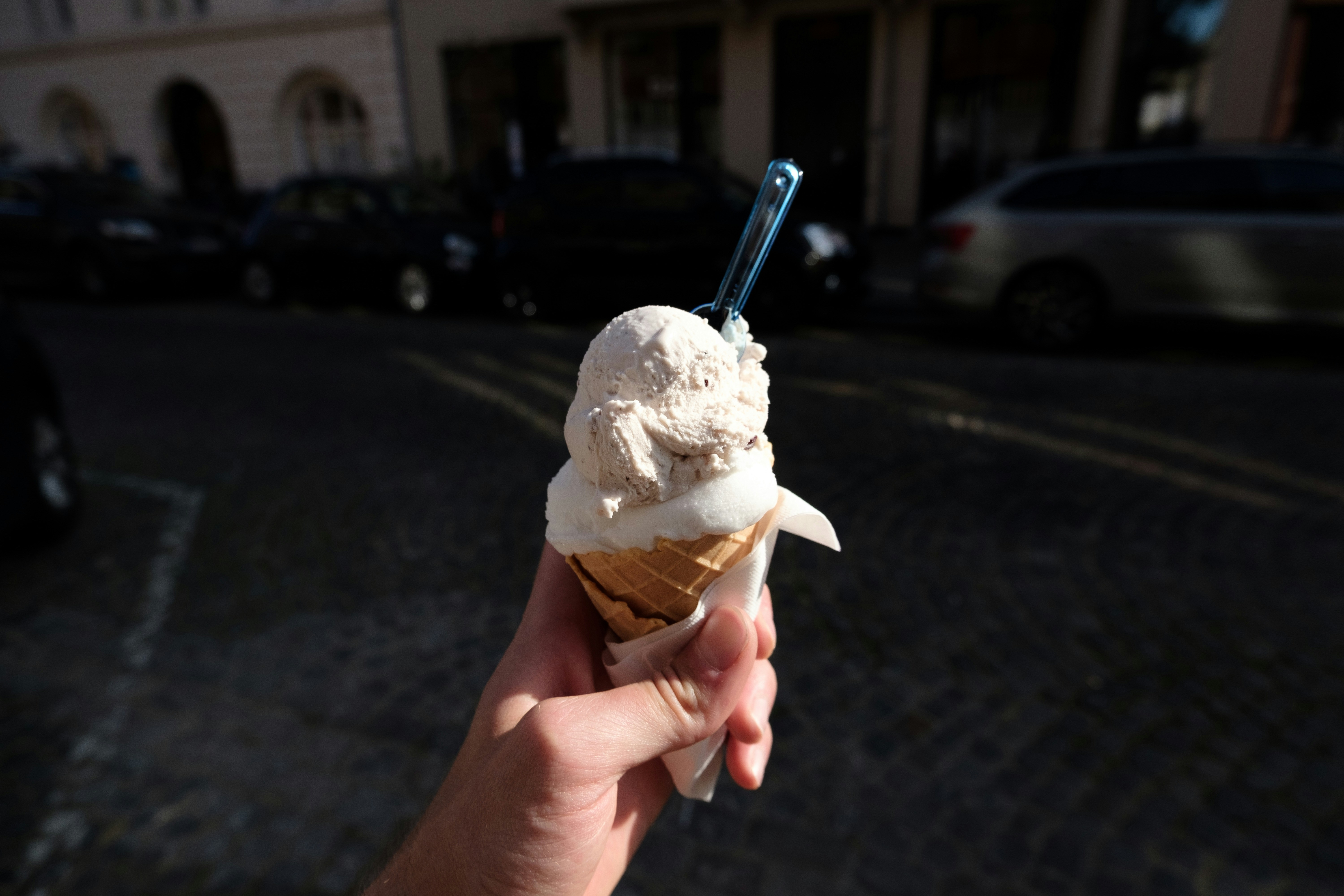 Vanilla Scoop, City Glow: A Handheld Moment on Cobblestones