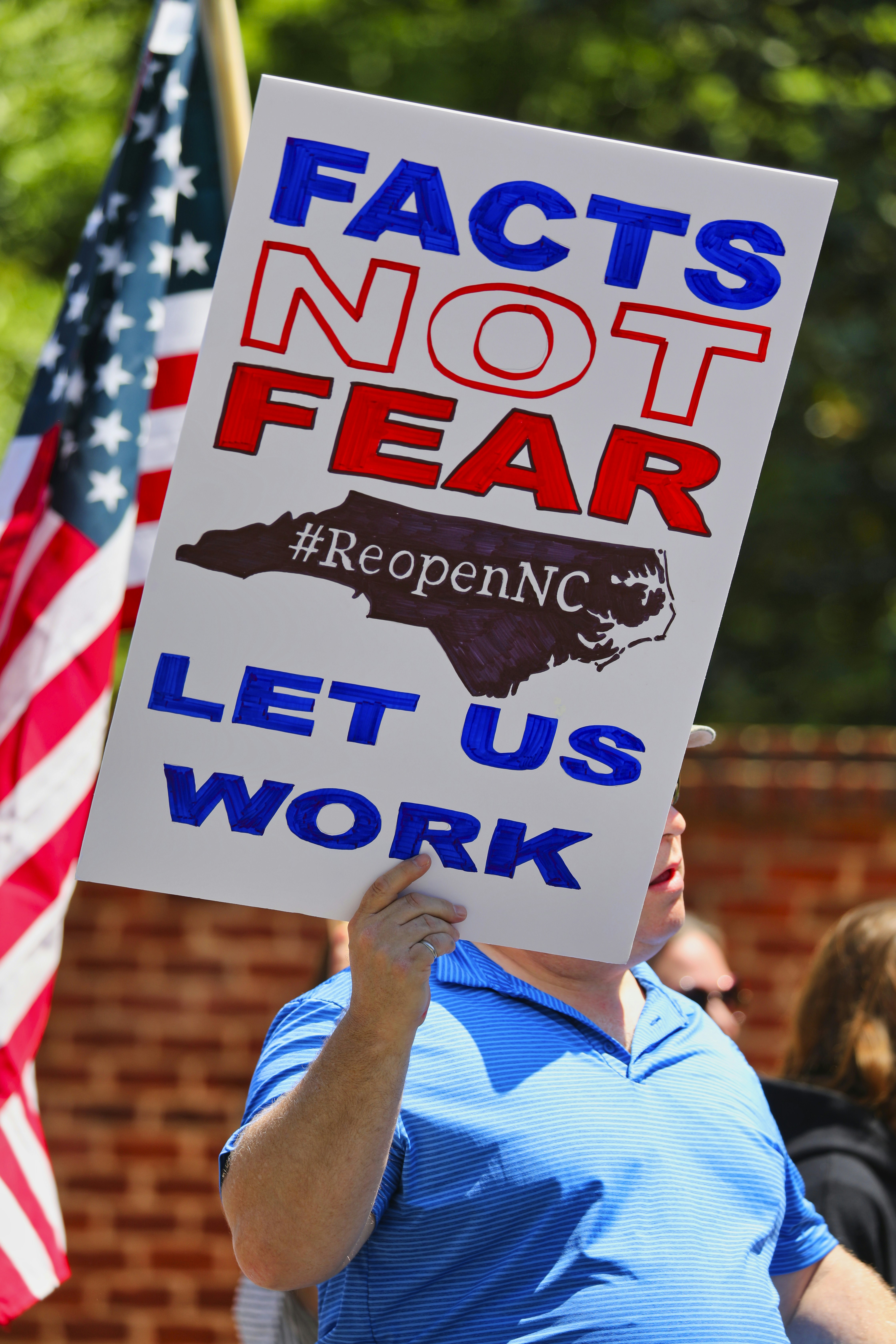Facts Not Fear: Let Us Work—A Rally Sign Illuminating a Daylight Moment