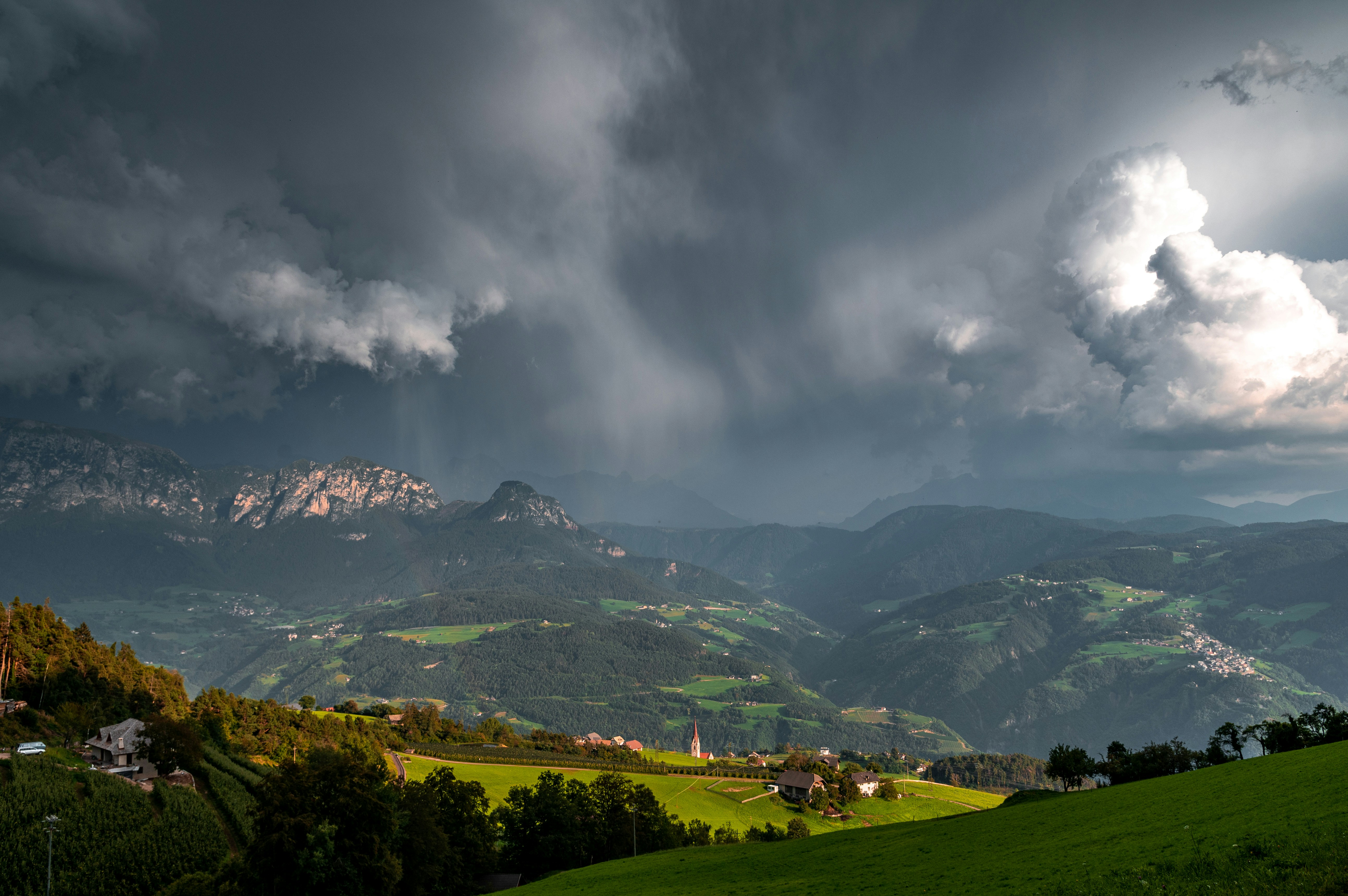 Church Spire at Storm's Edge: A Green Valley Beneath a Roiling Sky