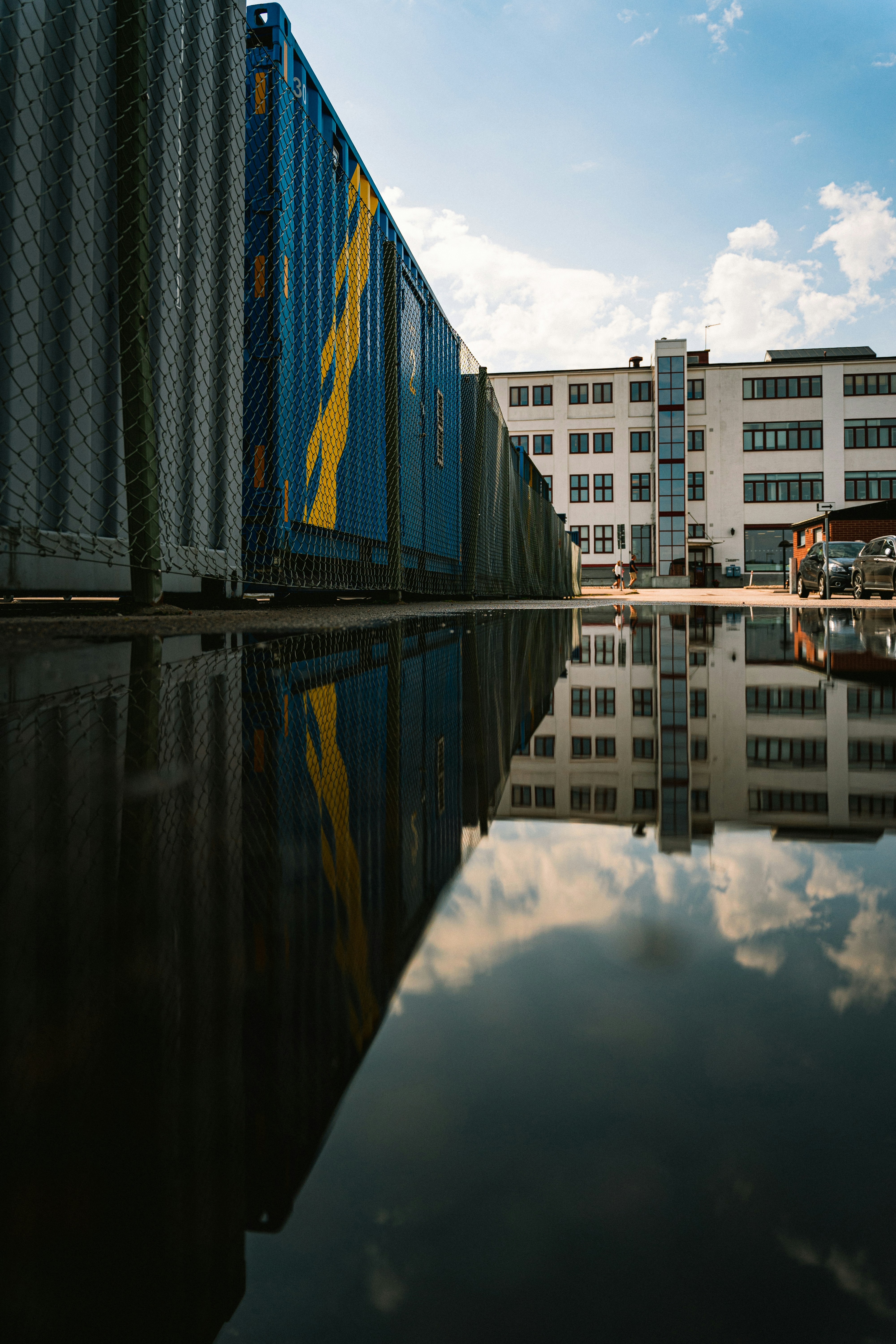 Mirror Edge: A Quiet Industrial Alley Framed by Blue Fencing