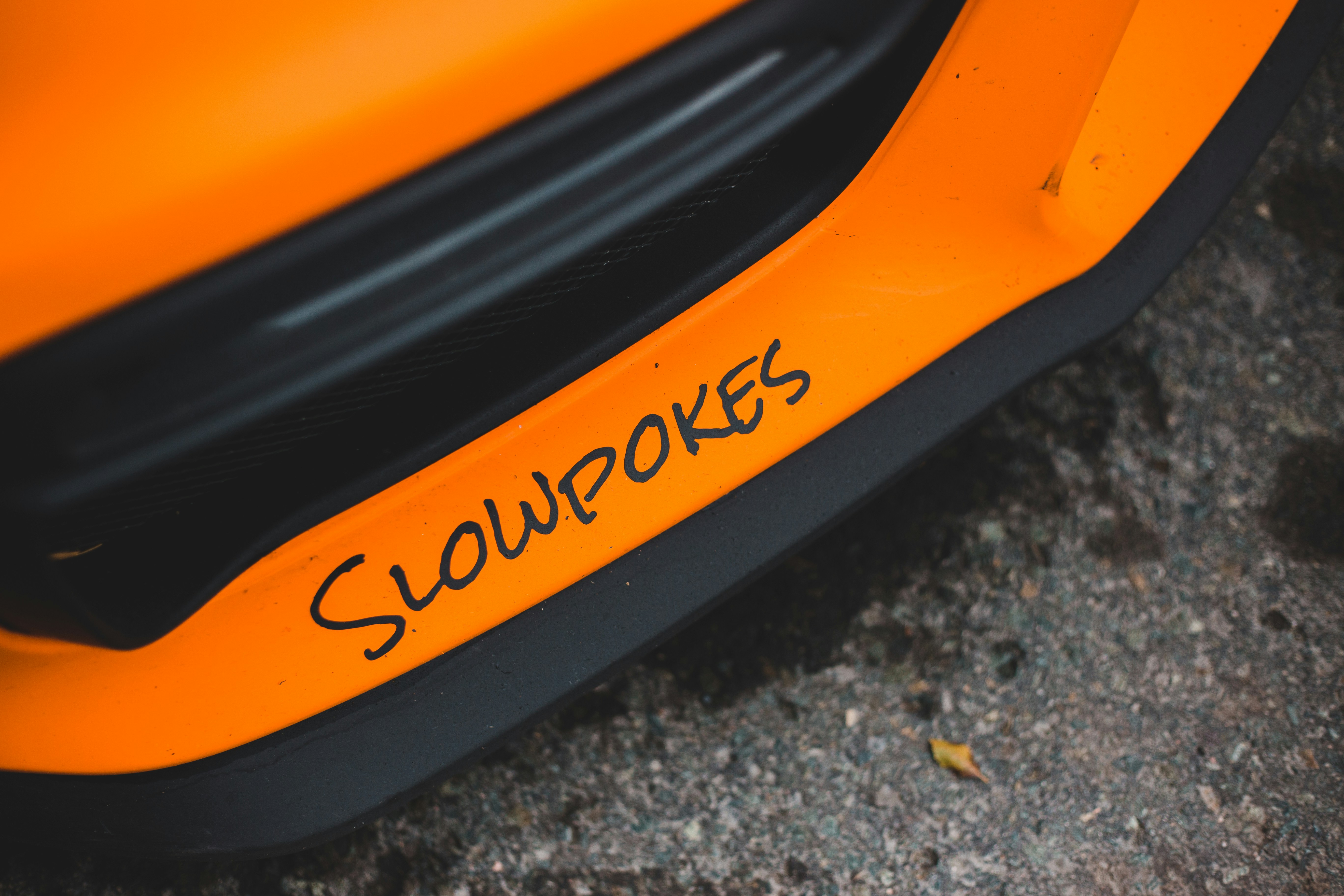 SLOWPOKES Scrawled on a Neon Orange Car Lip