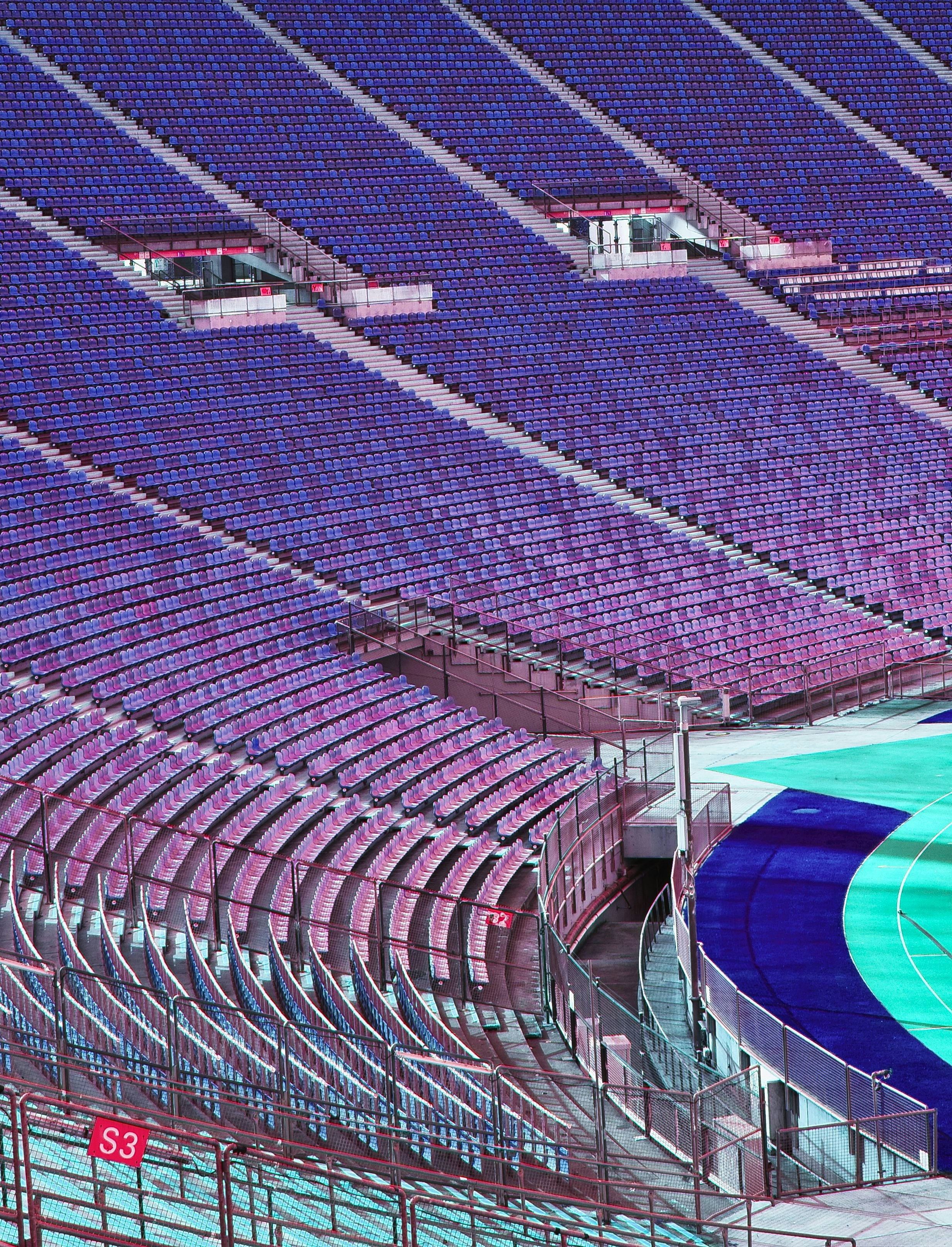 Vibrant seating arrangement in a stadium, showcasing alternating hues of purple and blue. The design creates a visually striking pattern across the stands.