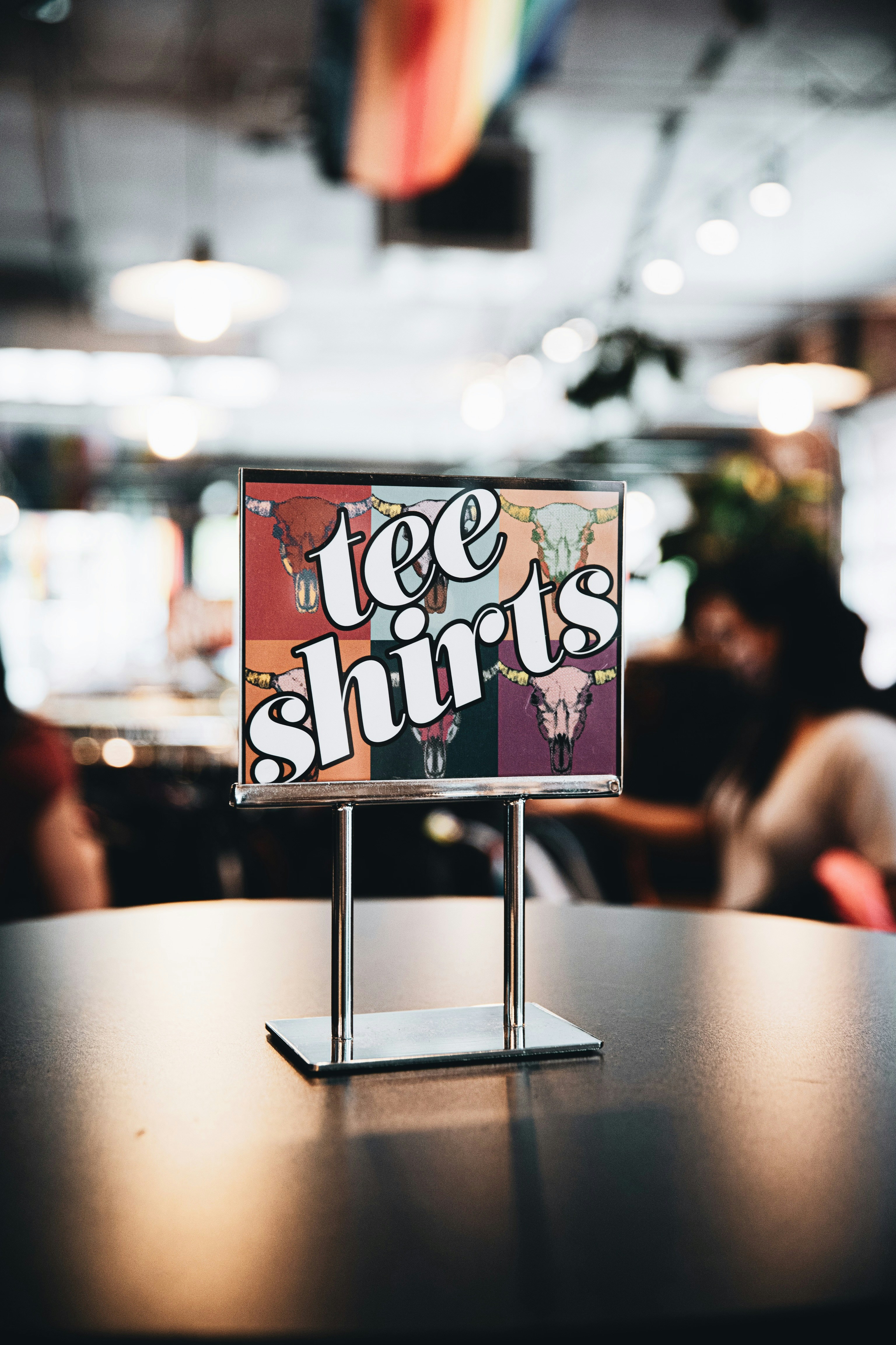 Colorful Signpost: 'tee shirts' Display in a Busy Cafe