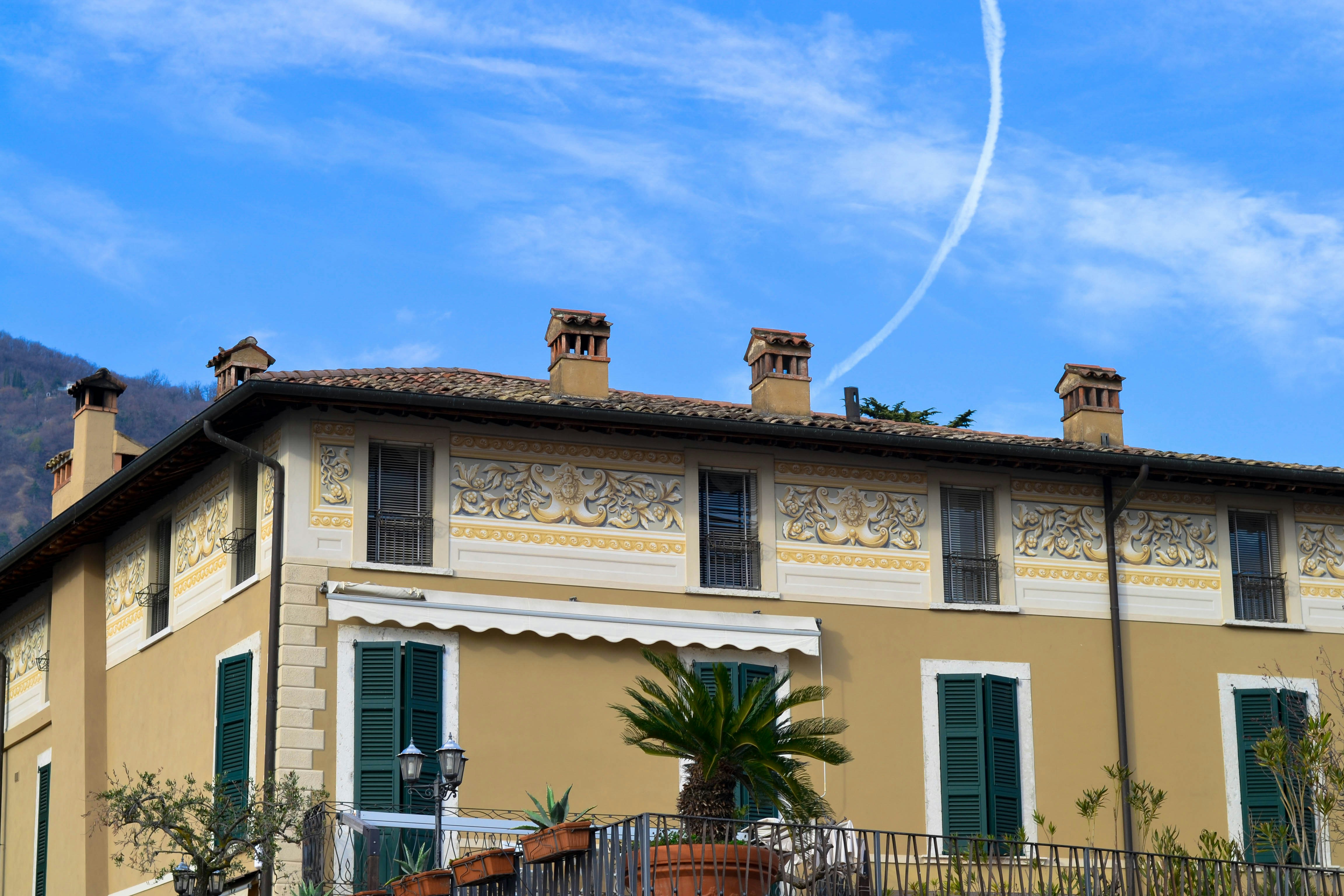 Sunlit Mediterranean Villa Facade Beneath a Winding Contrail