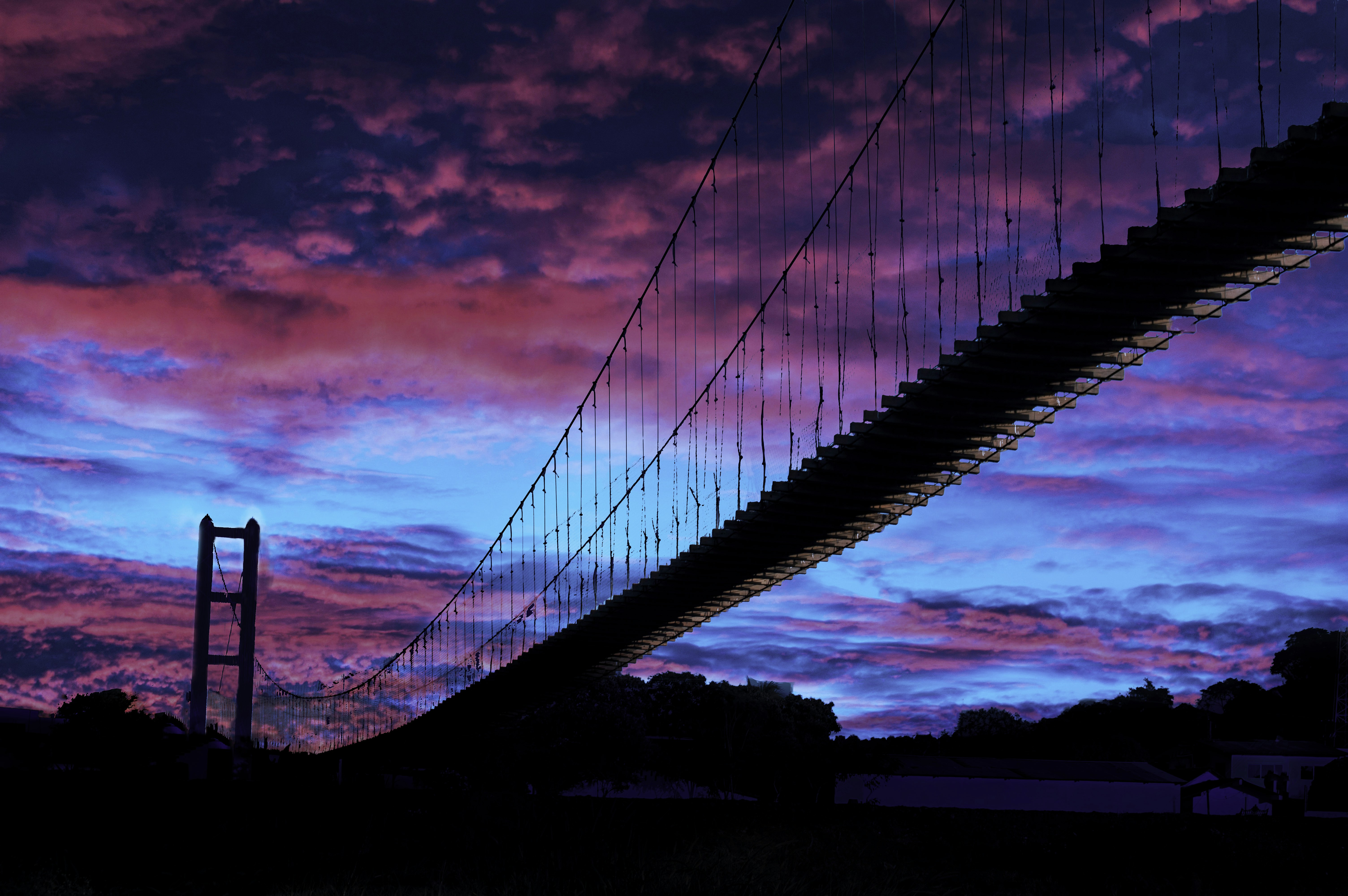 Crimson Sky over a Silent Suspension Bridge at Dusk