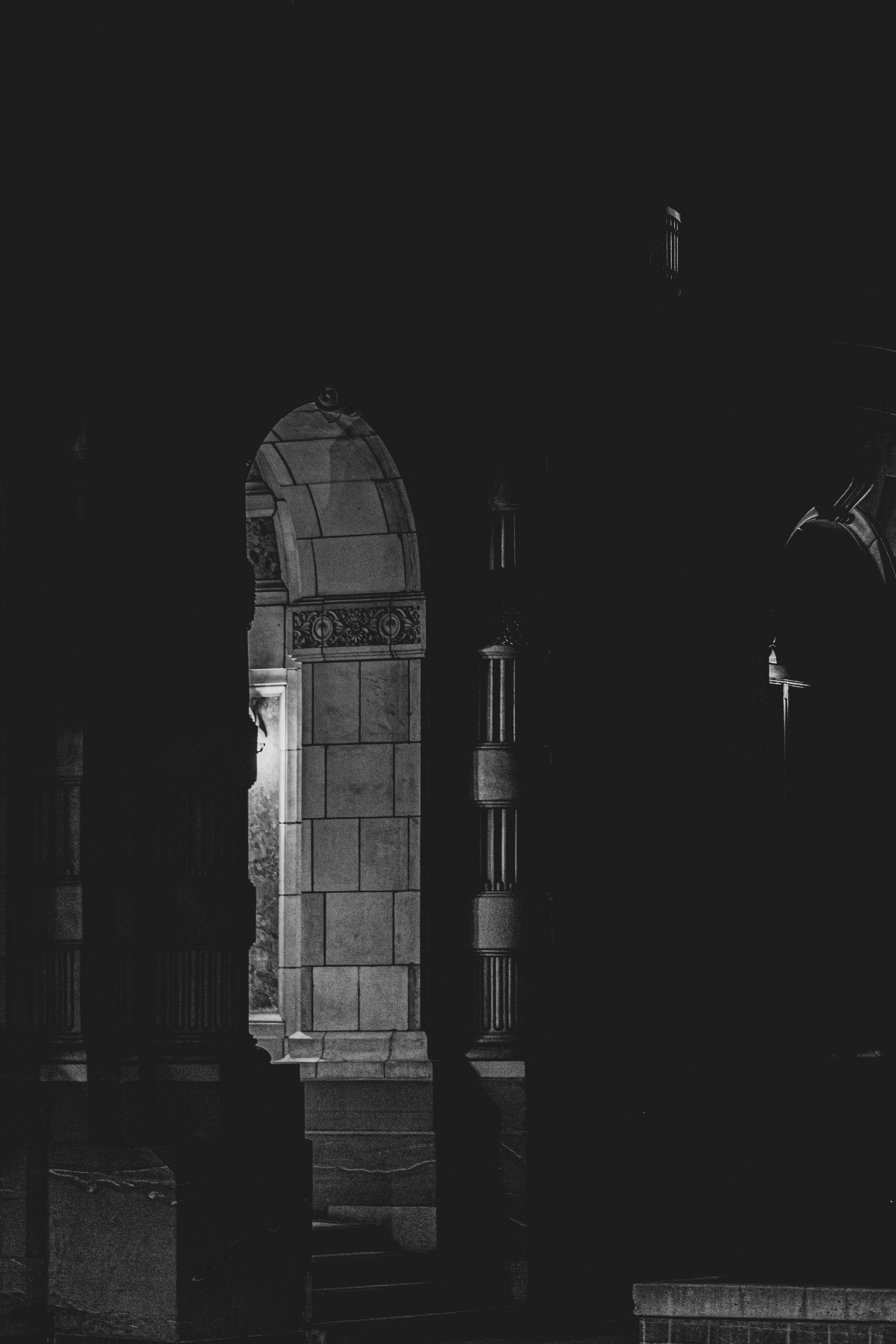 Intricate stone arches framed against deep shadows, revealing a glimpse of light that highlights the architectural details.