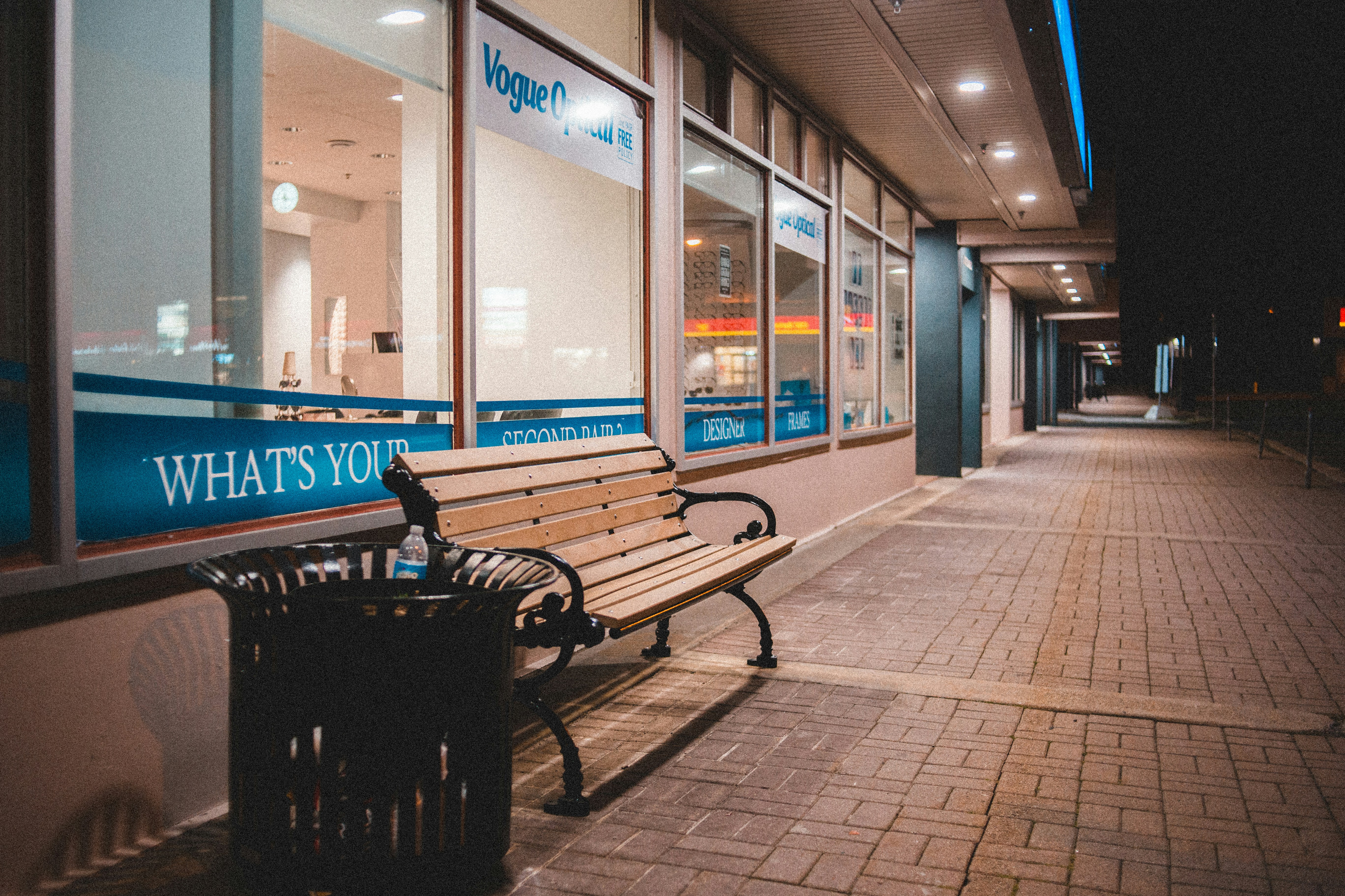 Bench Under Night Neon: Quiet Walk Along Glass-Fronted Shops