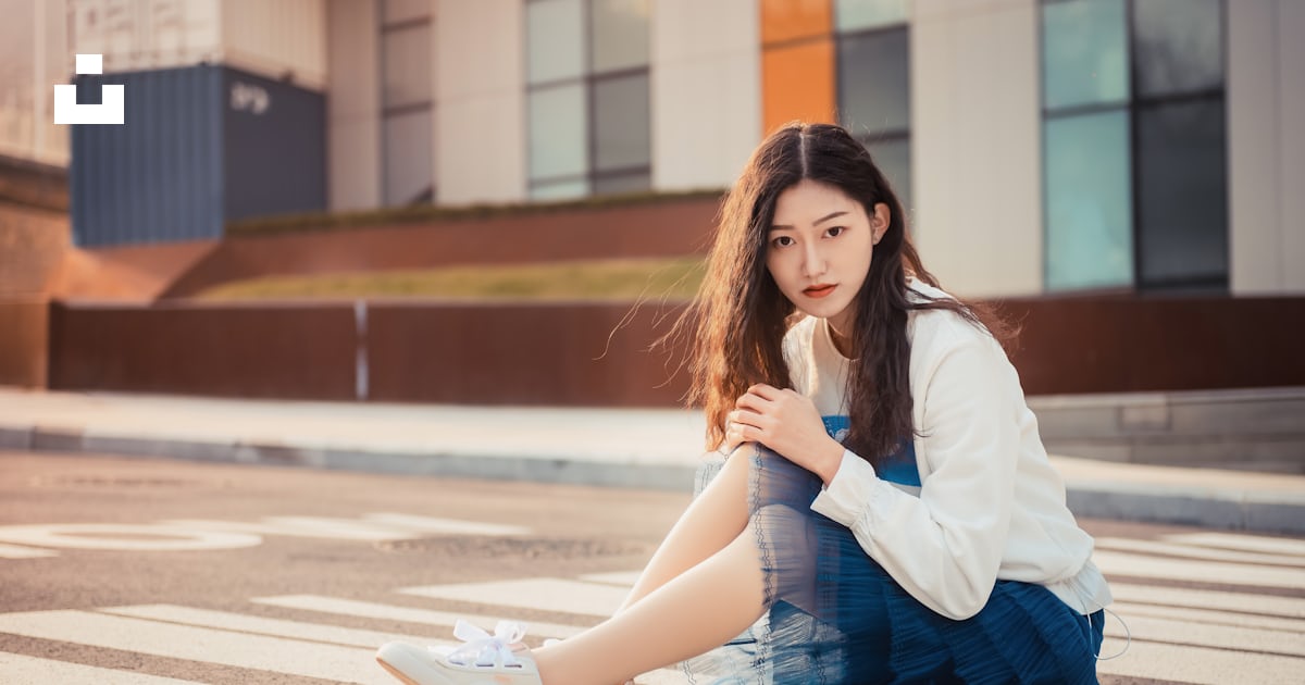 흰색 긴팔 셔츠와 파란색 데님 청바지를 입은 여자가 콘크리트 바닥에 앉아 있다 사진 Unsplash의 무료 사람의 이미지