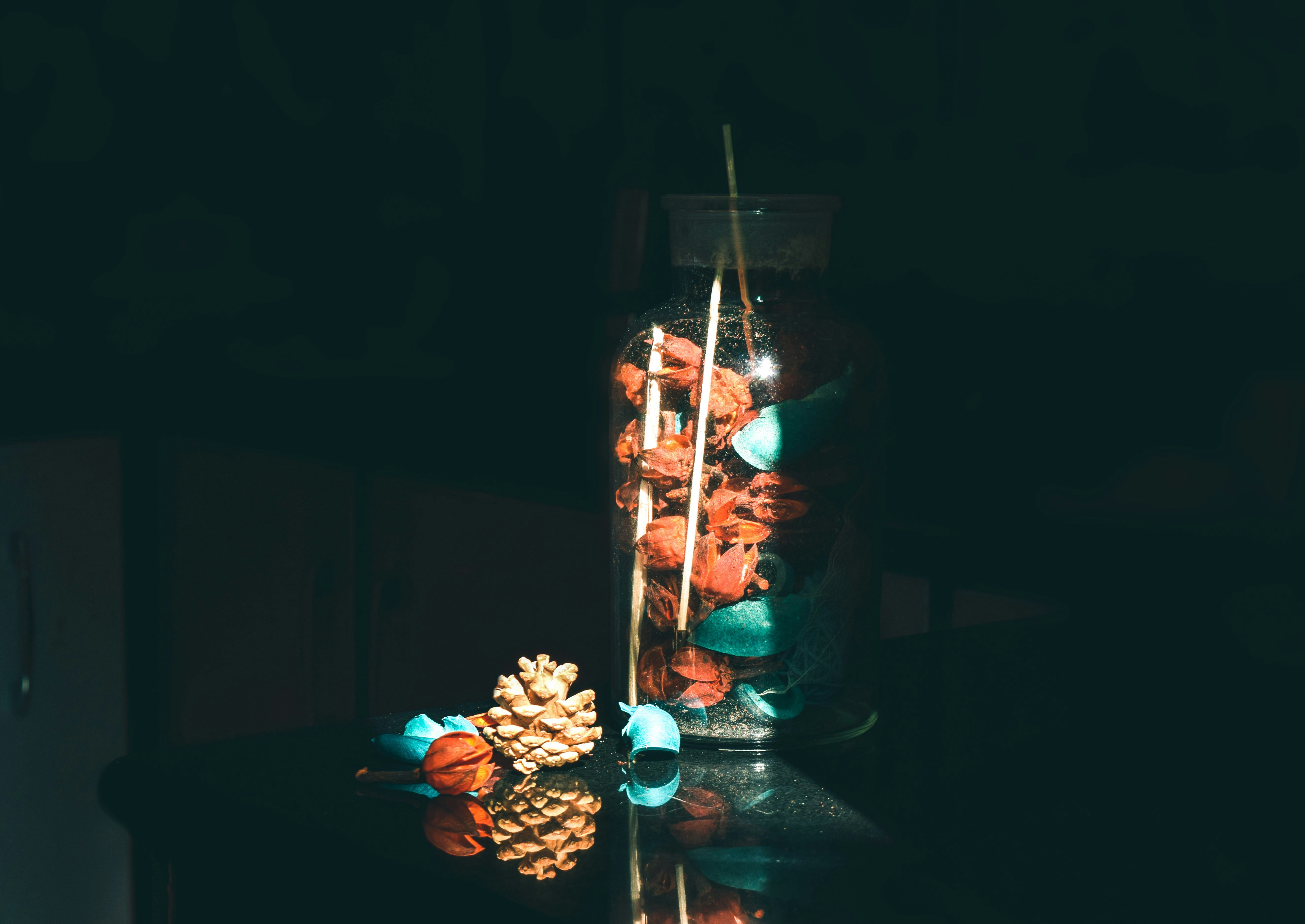Glass jar filled with colorful objects, illuminated against a dark background.