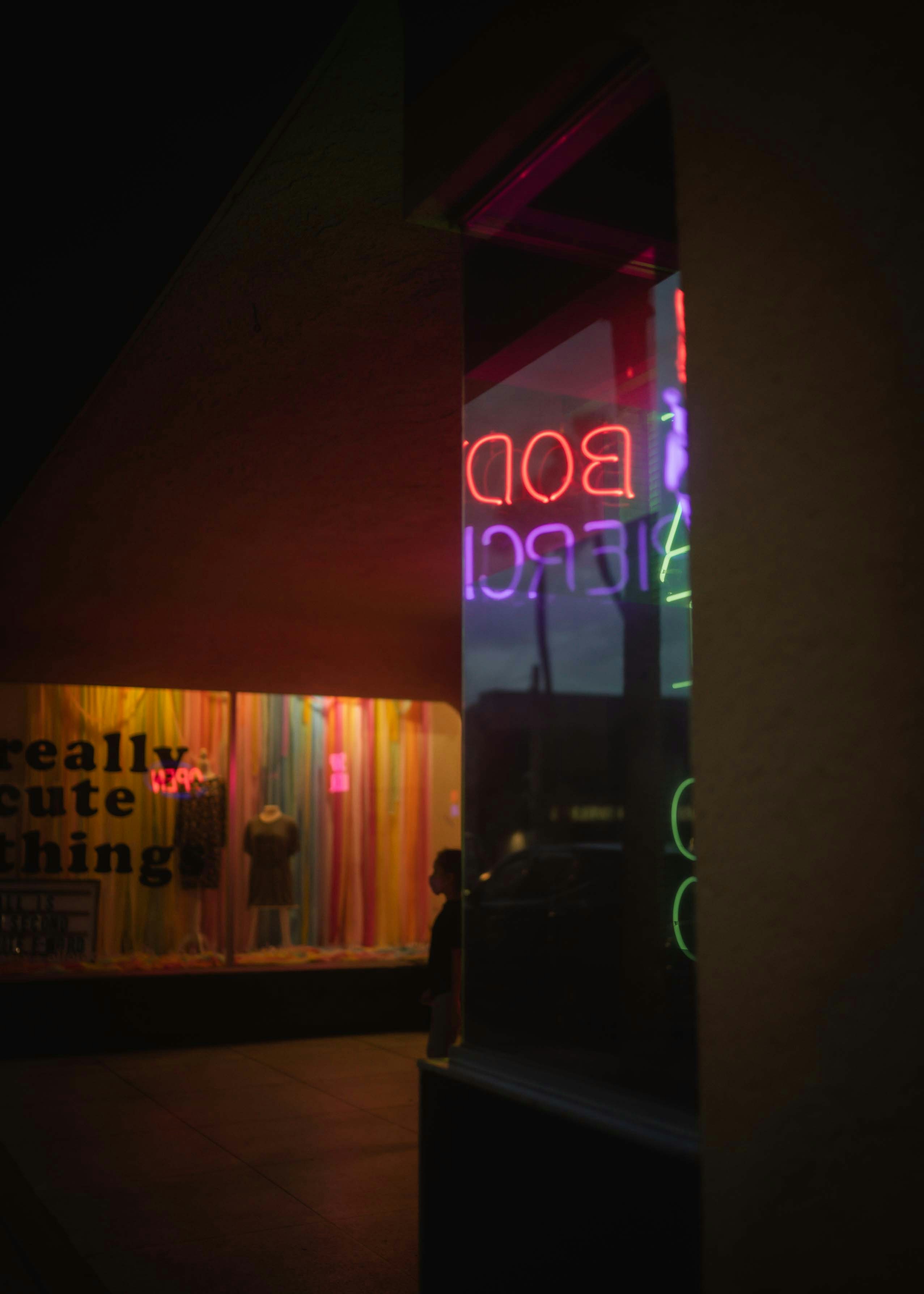 Neon store window reflections on a dark street