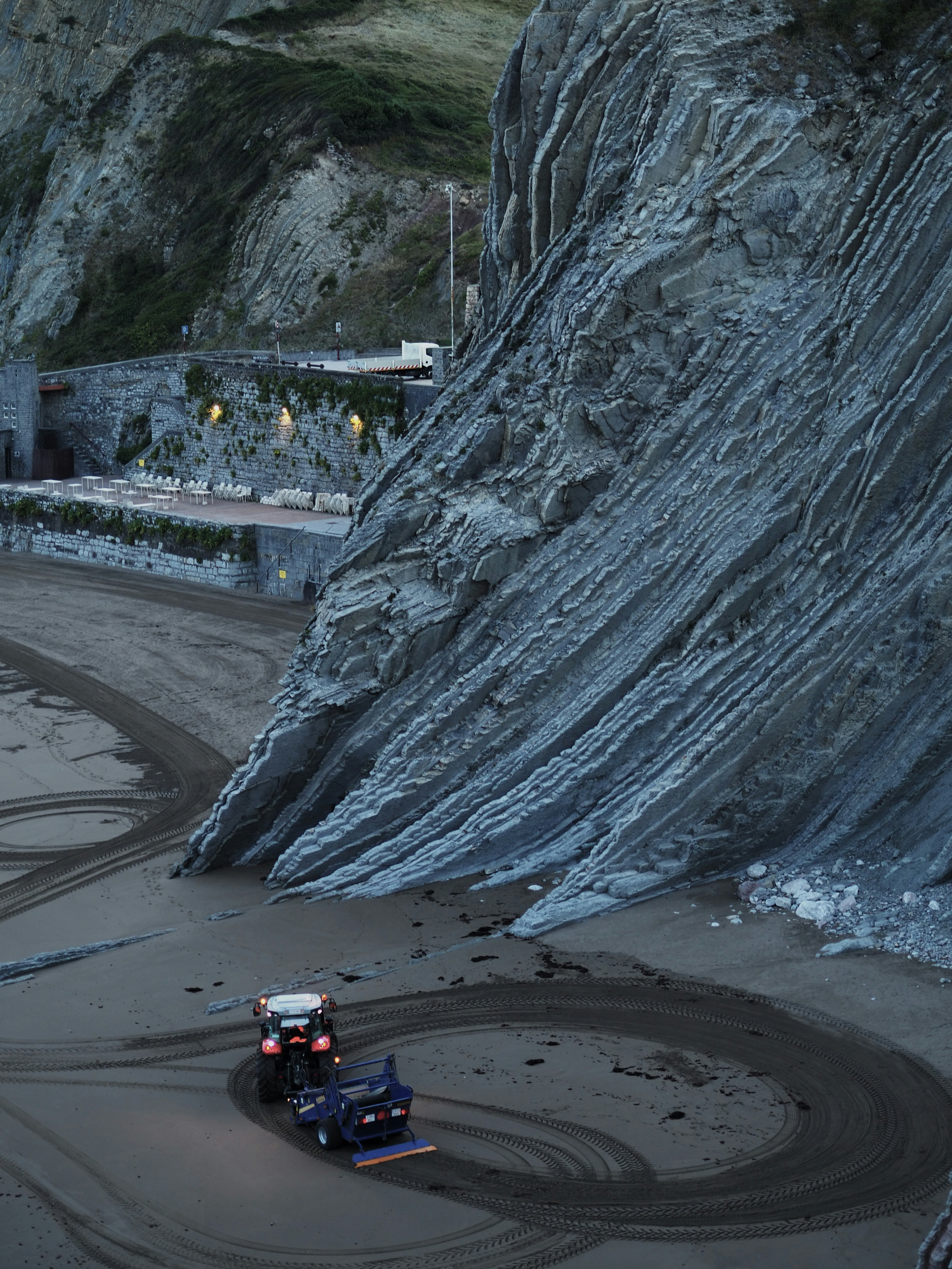 Wheel Tracks in Moonlit Shore: A Tractor Toward the Cliff