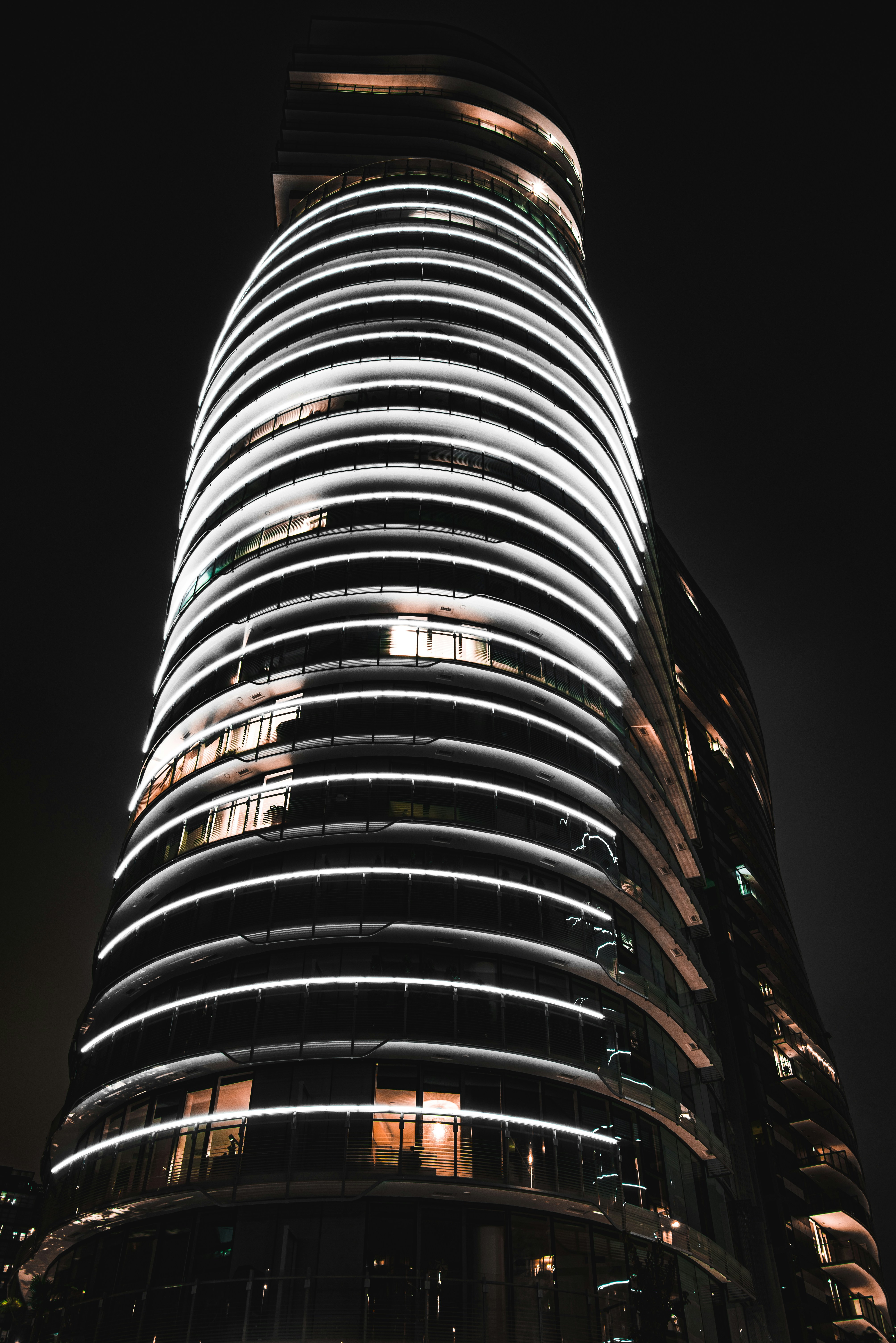A sleek, modern building illuminated by striking LED lines, showcasing its unique curved design against the night sky.