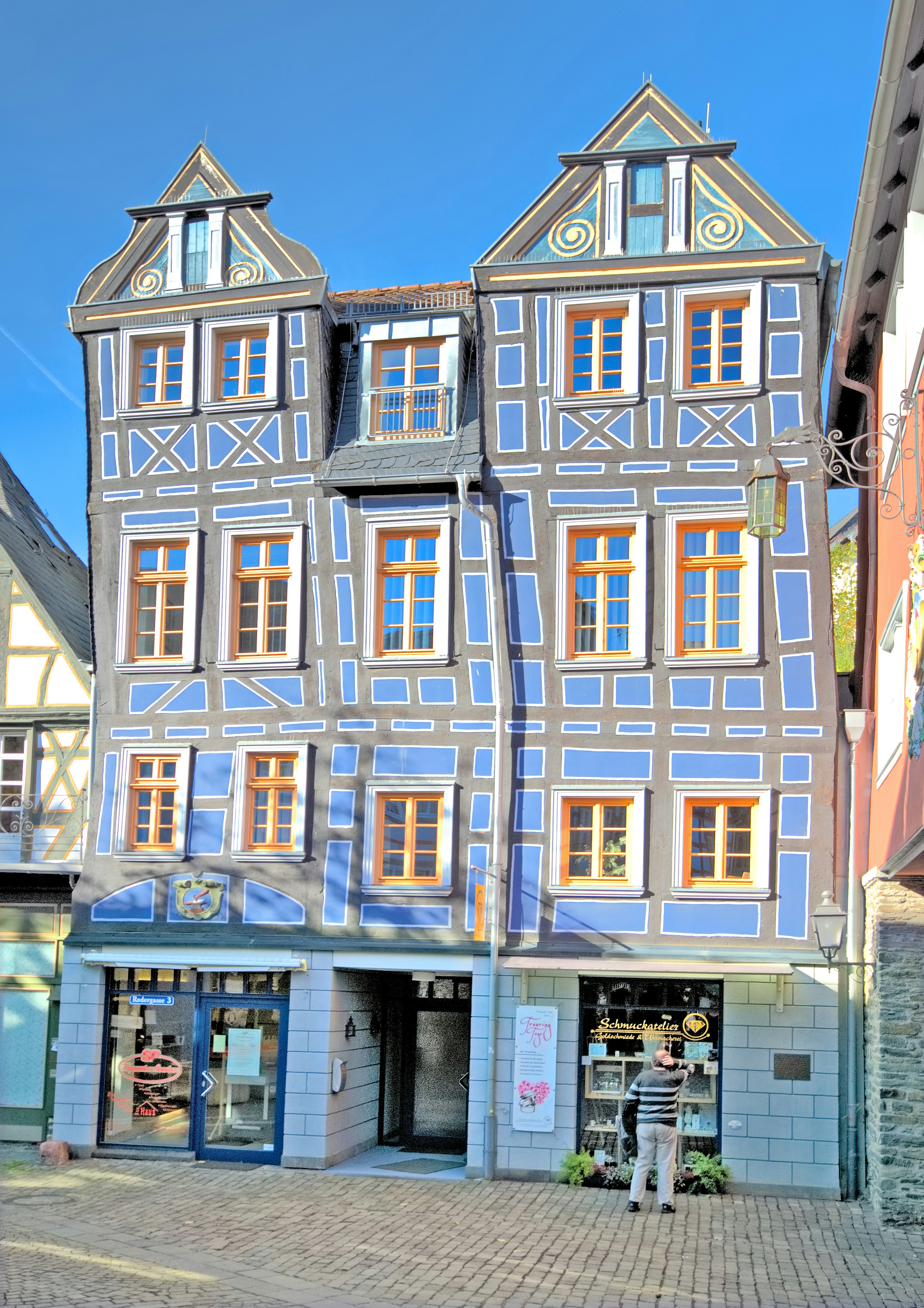 Colorful half-timbered building with ornate windows and a charming storefront in a historic town setting.