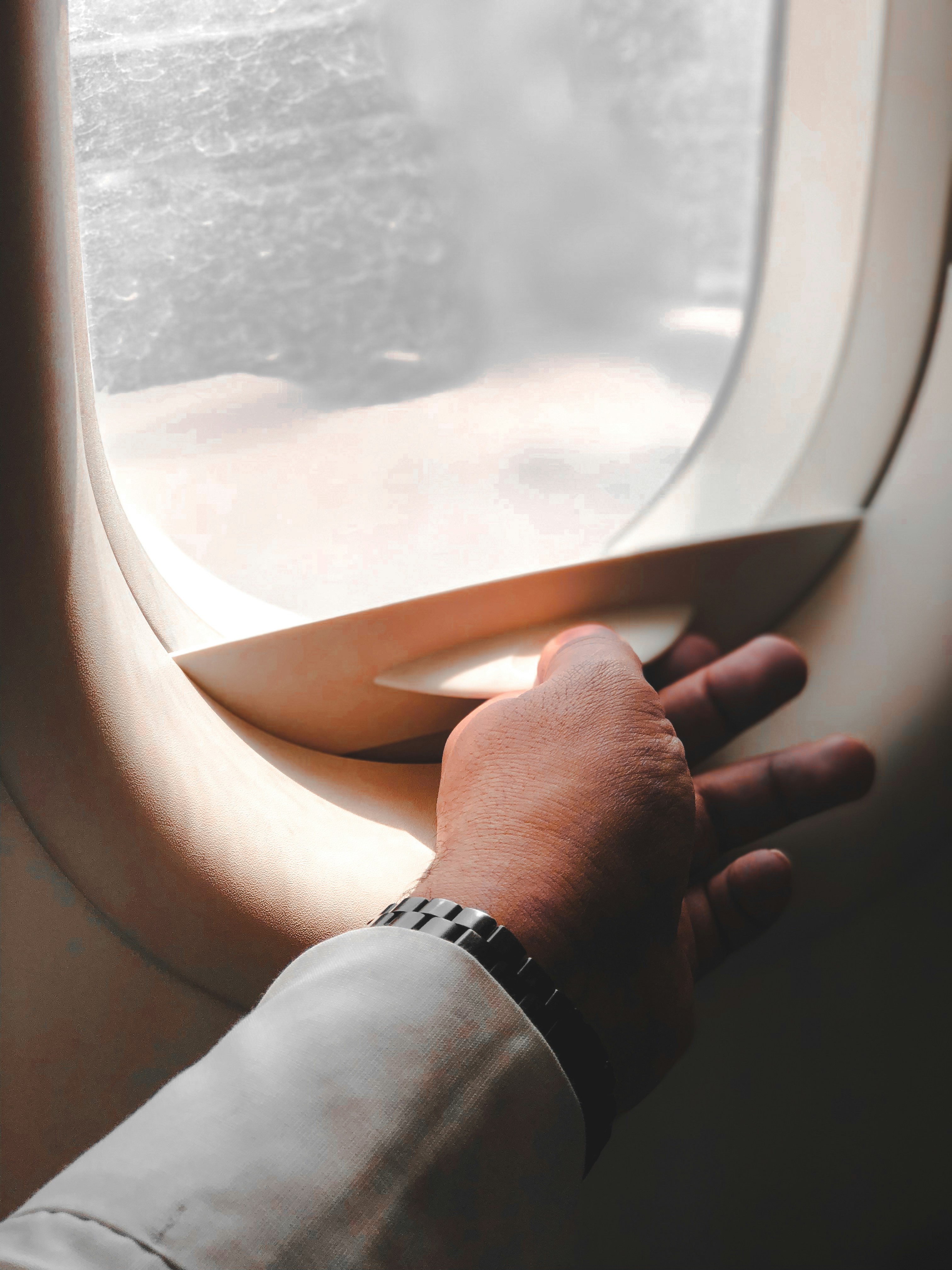 Tethered Light: A Passenger's Hand Adjusting the Plane Window Shade