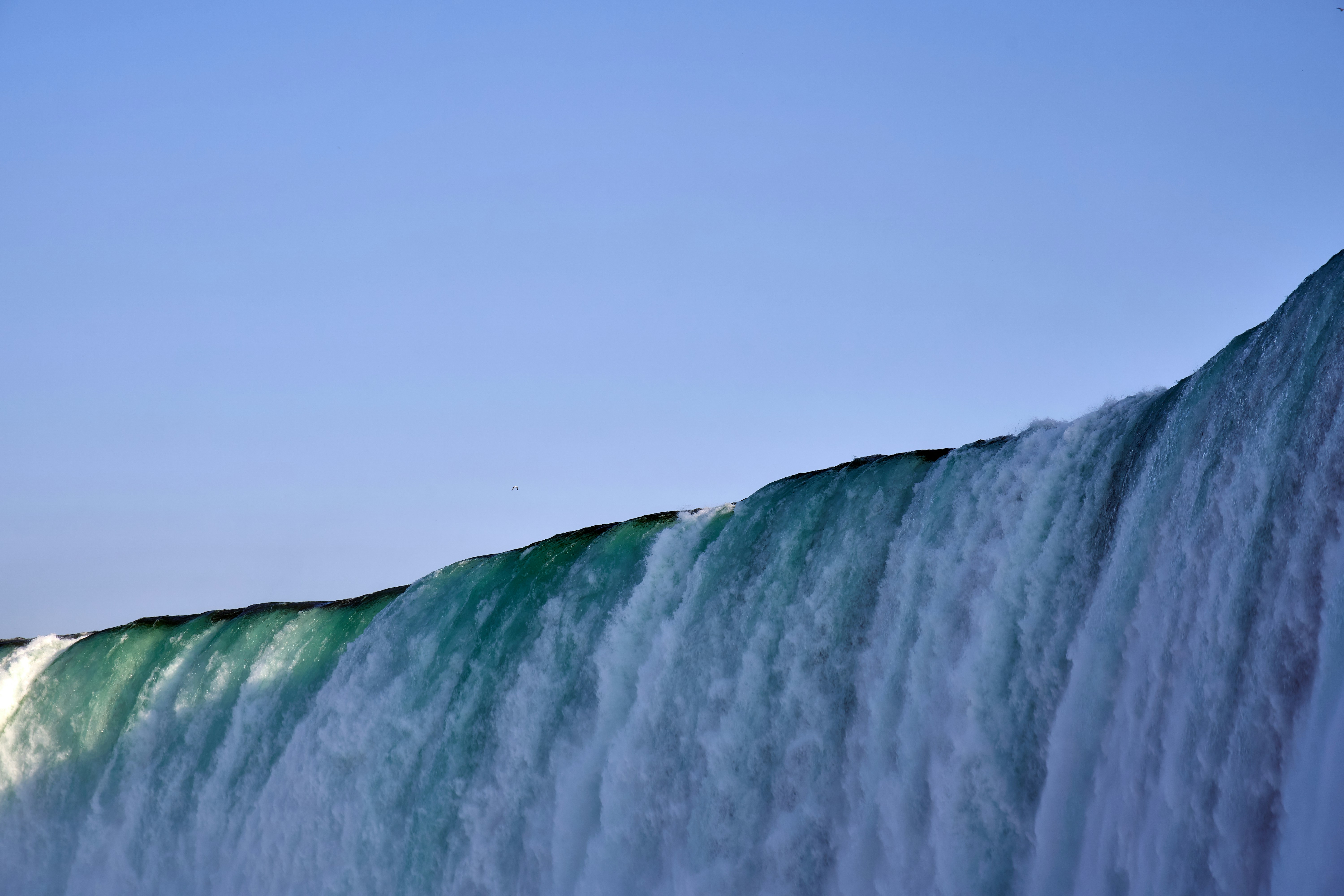 Majestic waterfall plunging over a rocky edge, showcasing the vibrant turquoise waters and mist rising into the air.