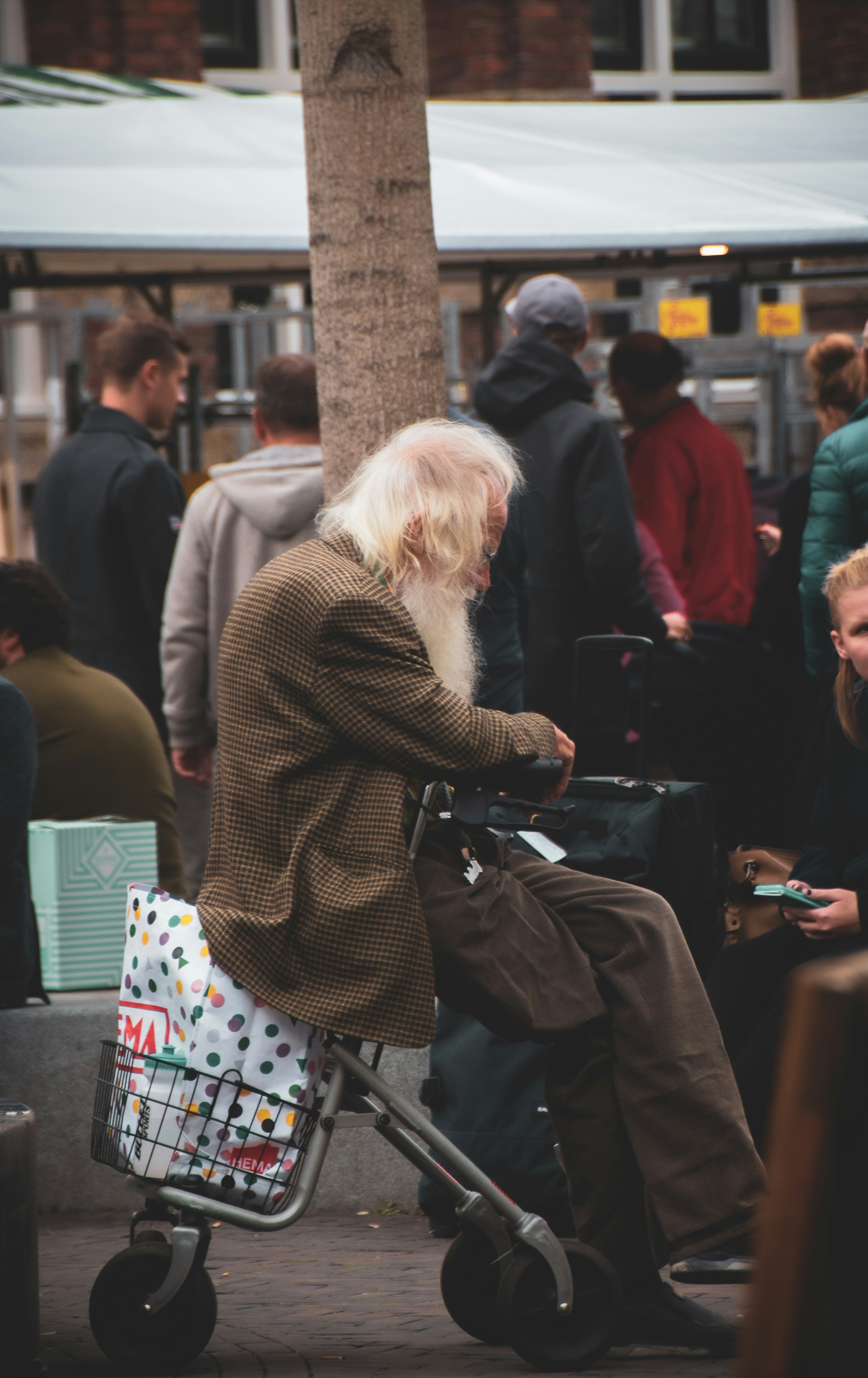 Beneath Market Light: An Elder on Wheels Among the Crowd