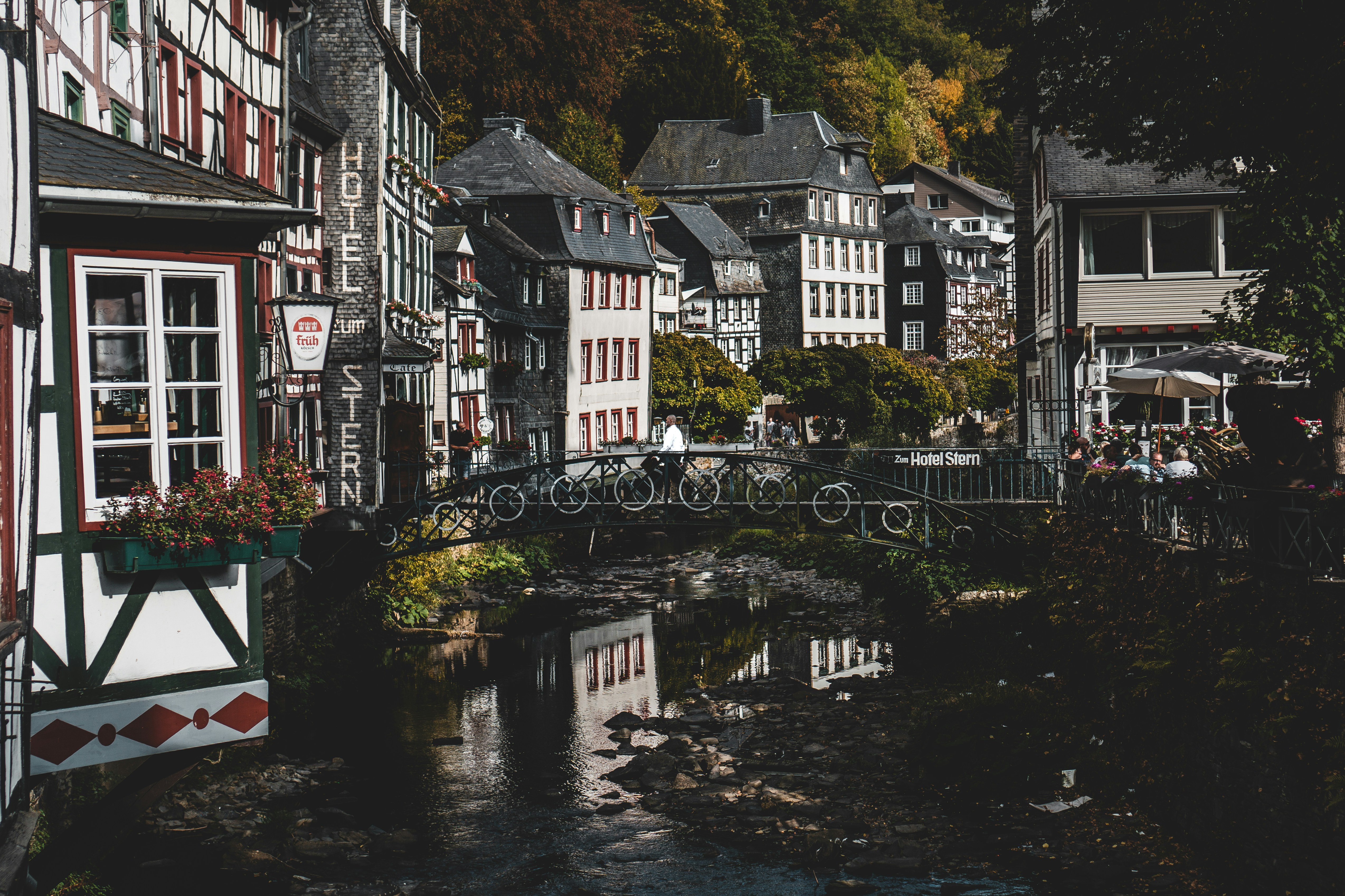 Quaint European village buildings reflected in a calm river under autumn foliage.