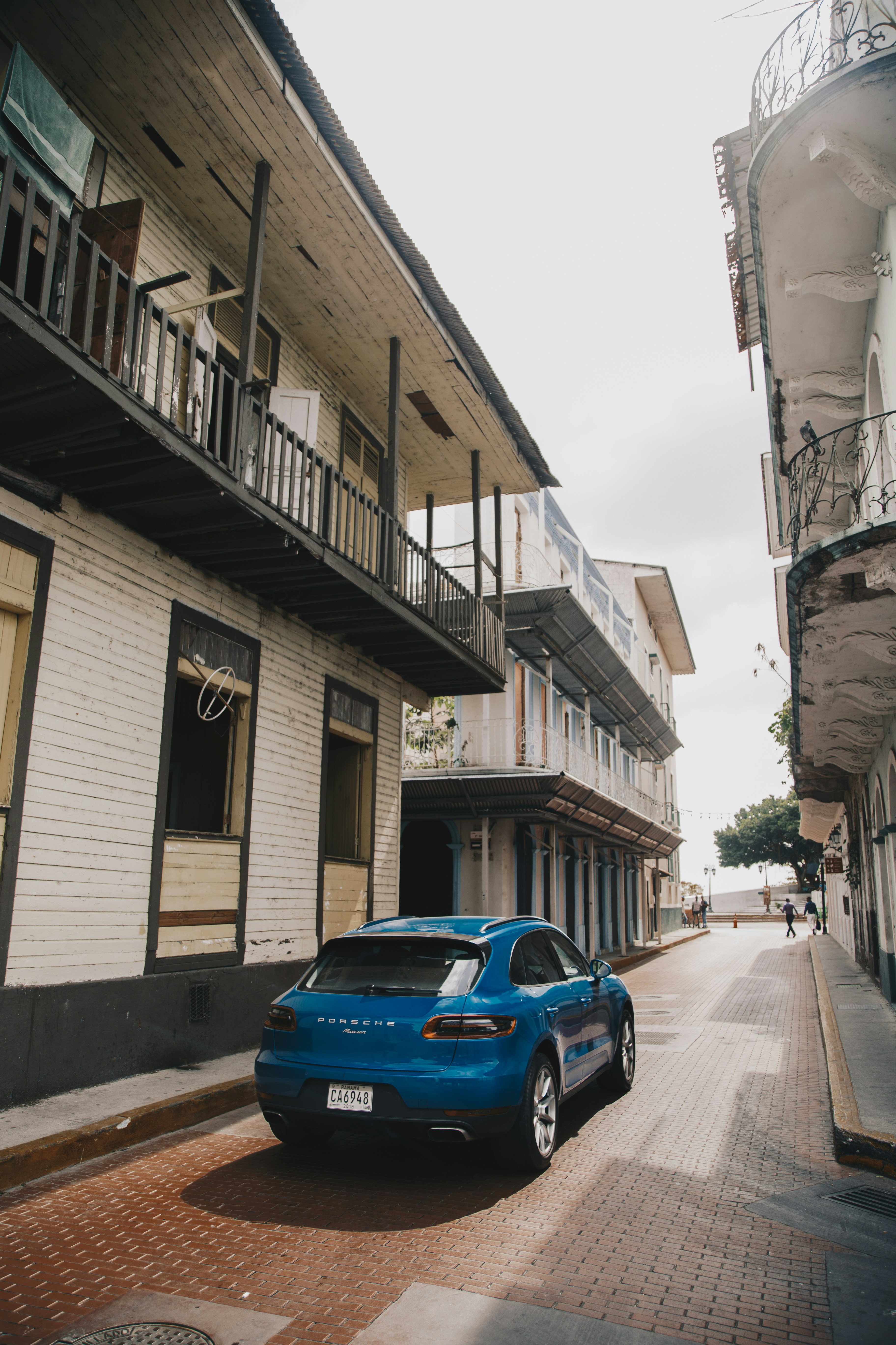 A blue Porsche parked on a cobblestone street flanked by historic buildings, capturing the blend of contemporary design and classic architecture.