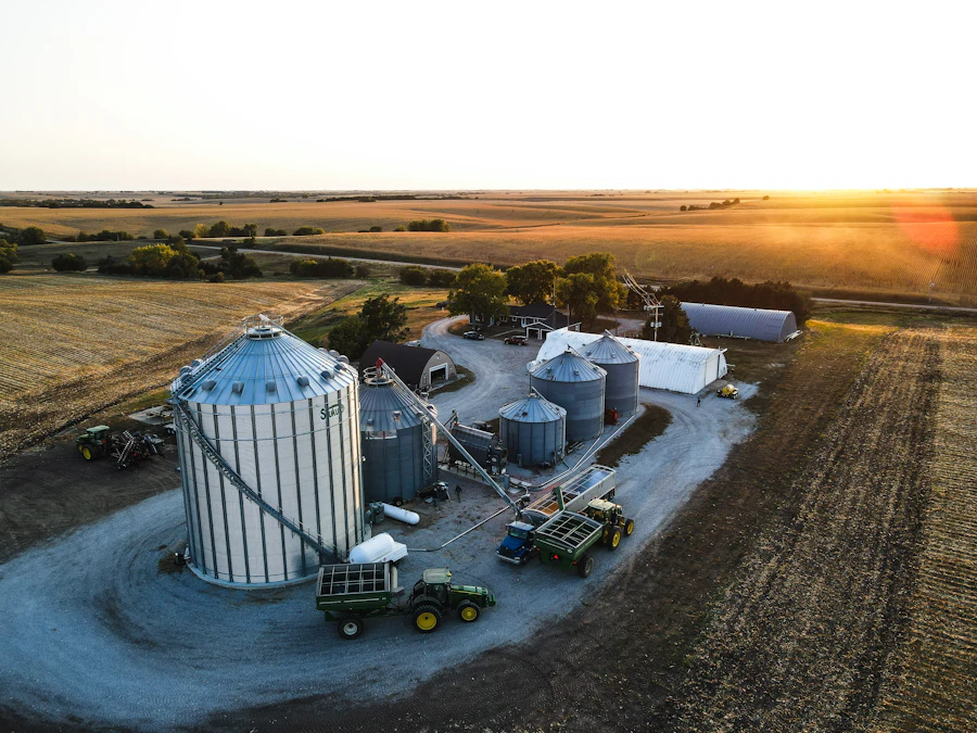 Aerial view of grain silos and equipment on a farm at sunset.