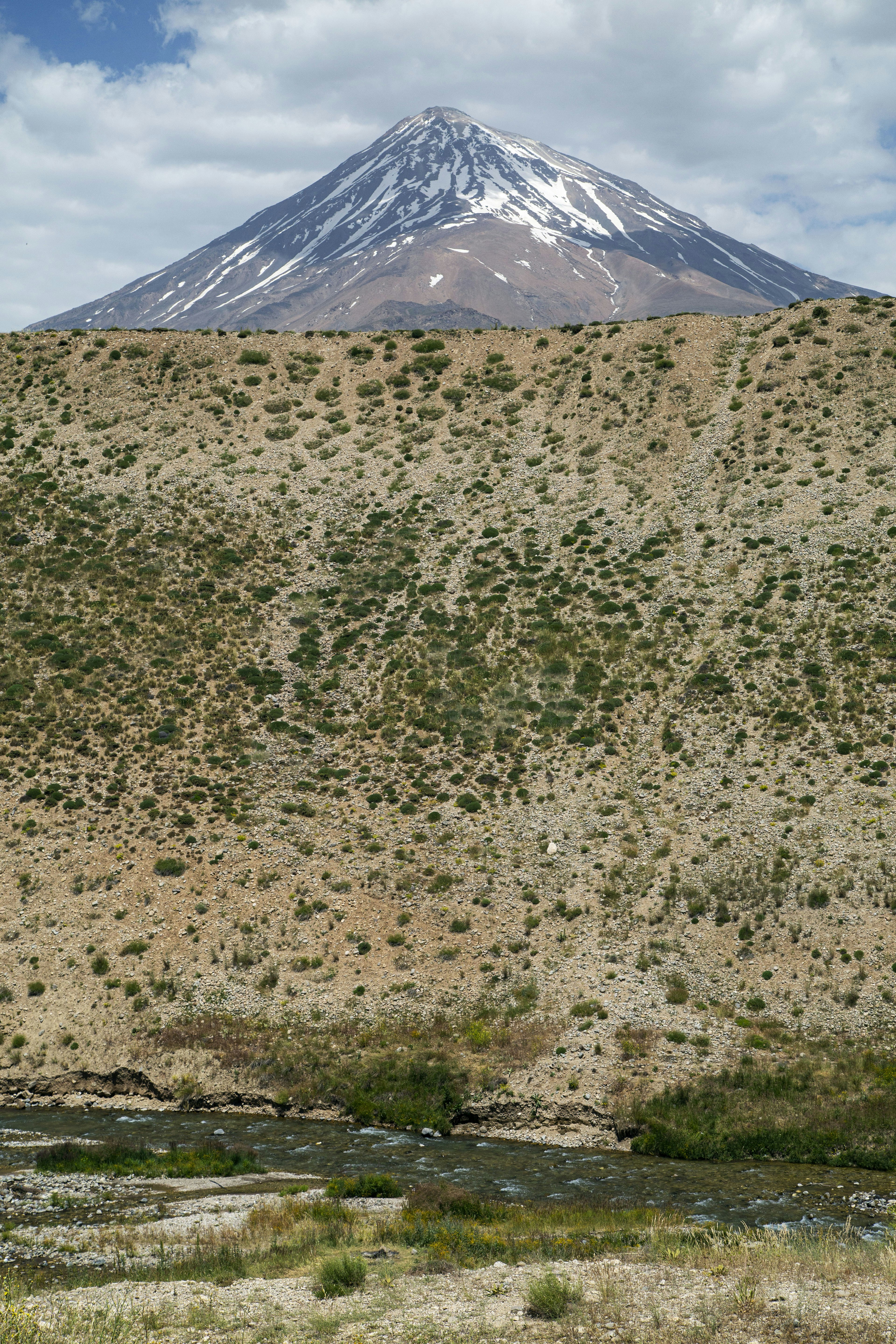 Snow-capped mountain towering over a rugged landscape, with a winding river at its base. The scene captures the essence of natural beauty and tranquility.