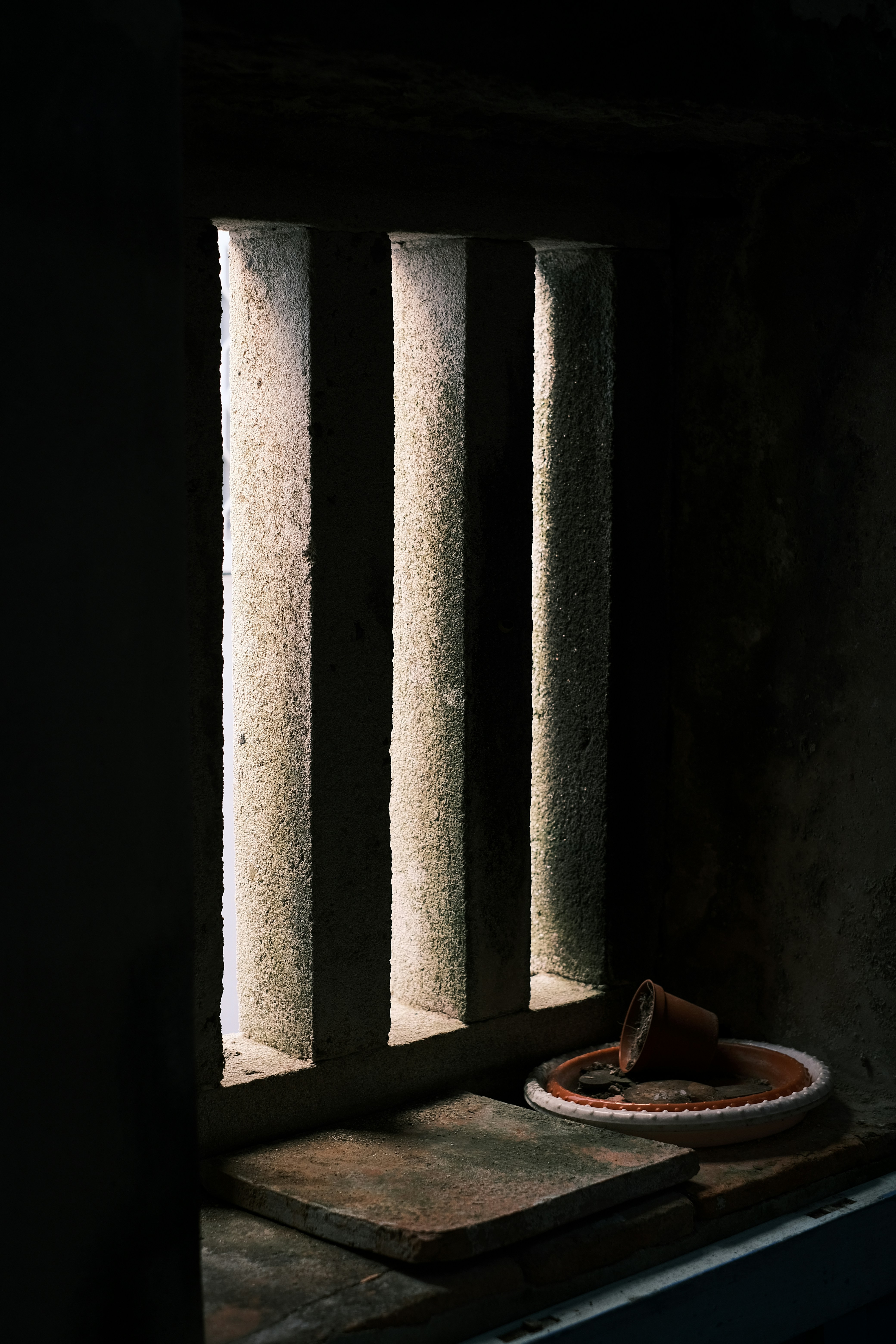 A slender beam through three concrete bars in a hushed, dusty interior