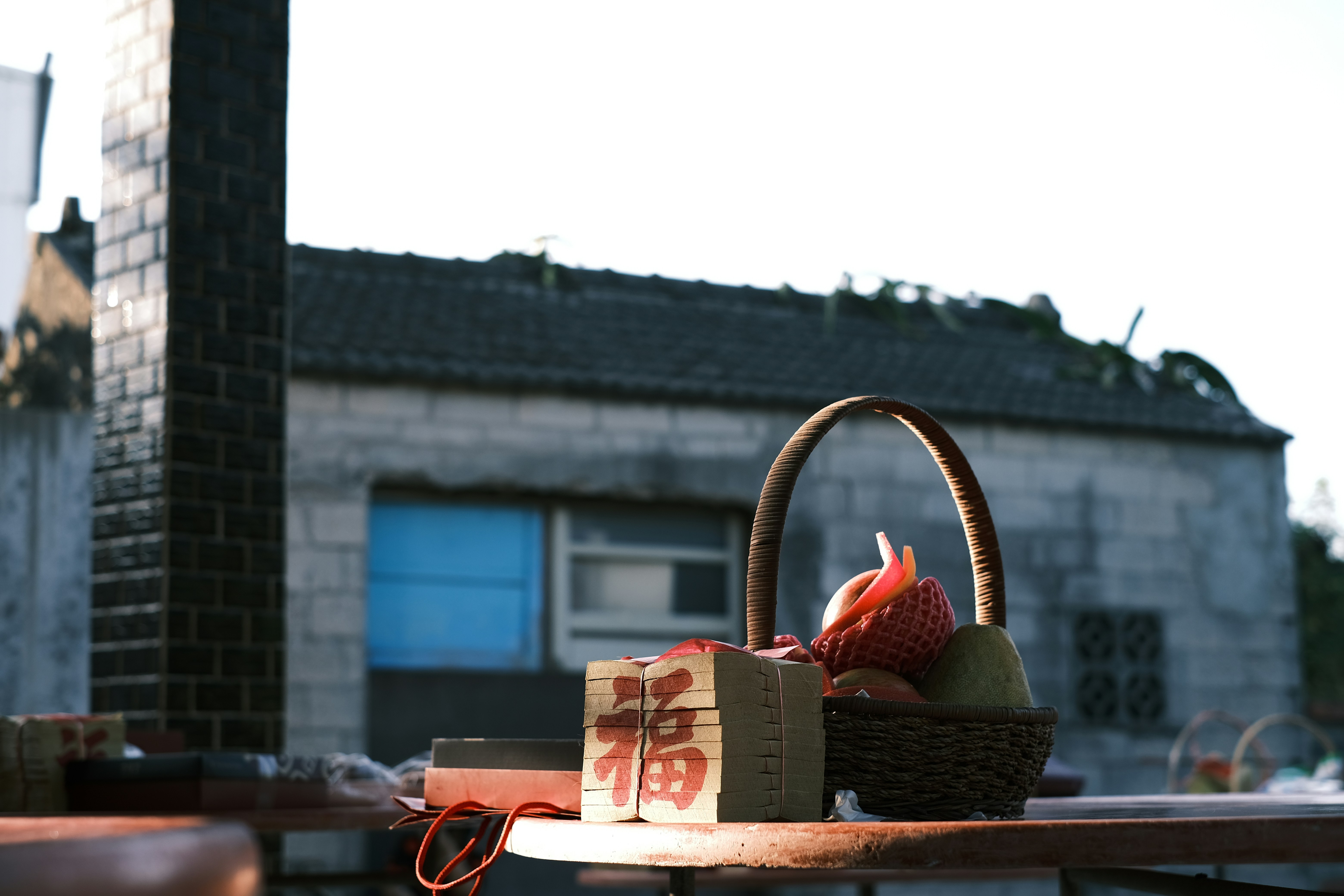 Fortune Basket: Fruit and a Red Envelope on a Sunlit Terrace Table