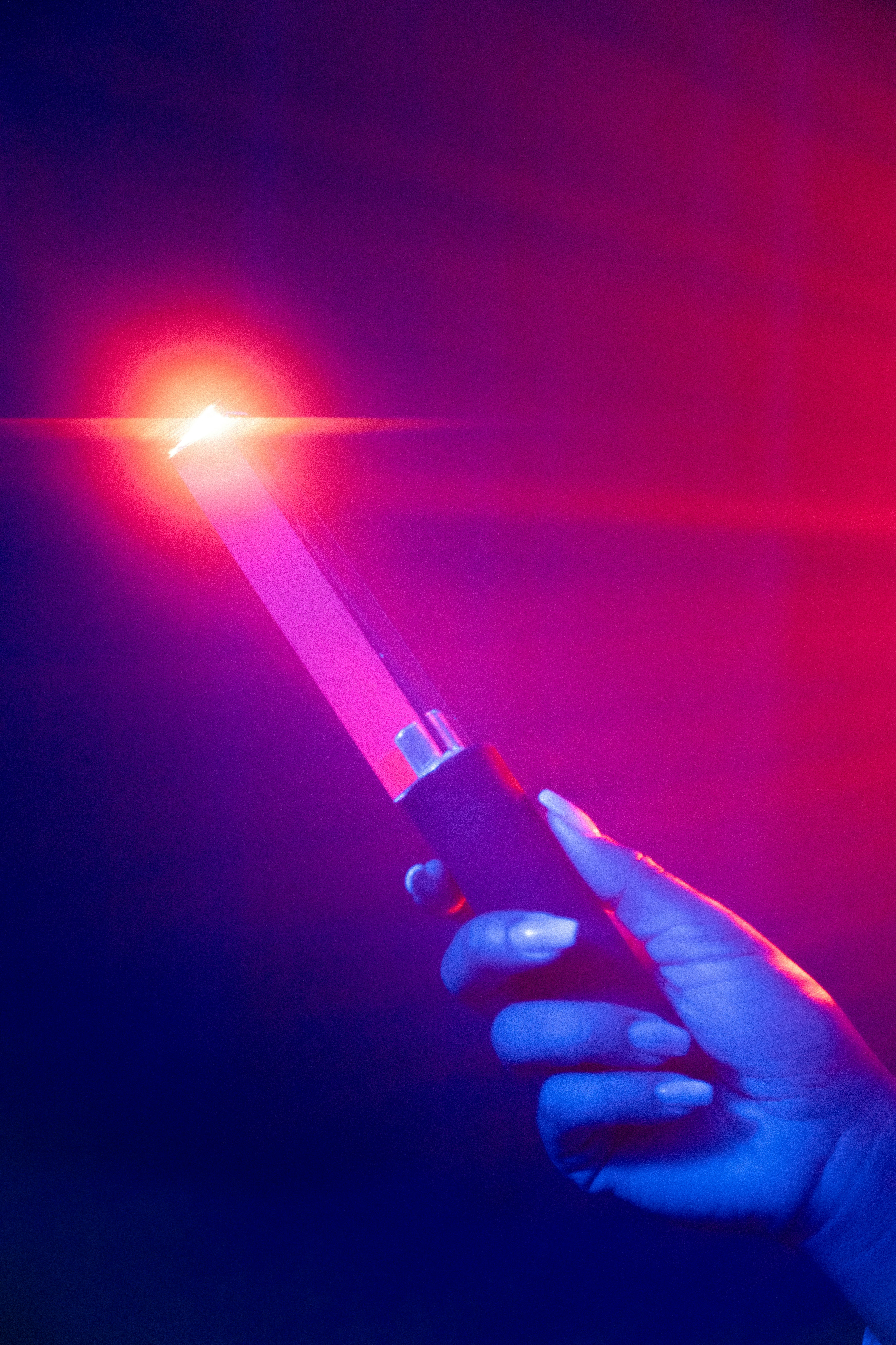 Neon-Blue Glow: Hand with Light-Emitting Knife under Vaporous Night