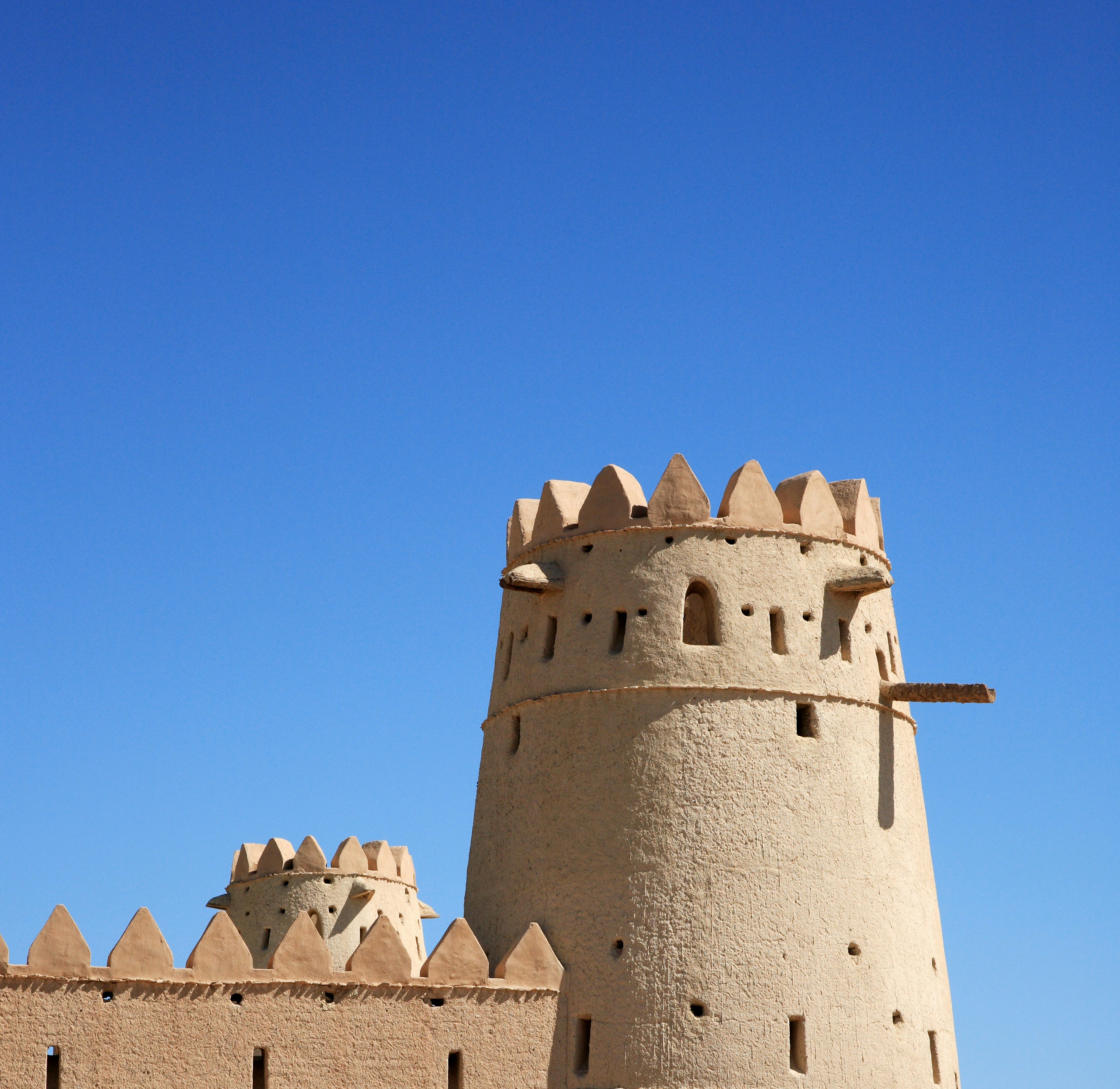 Historic desert fortress with distinct towers and battlements under a clear blue sky.