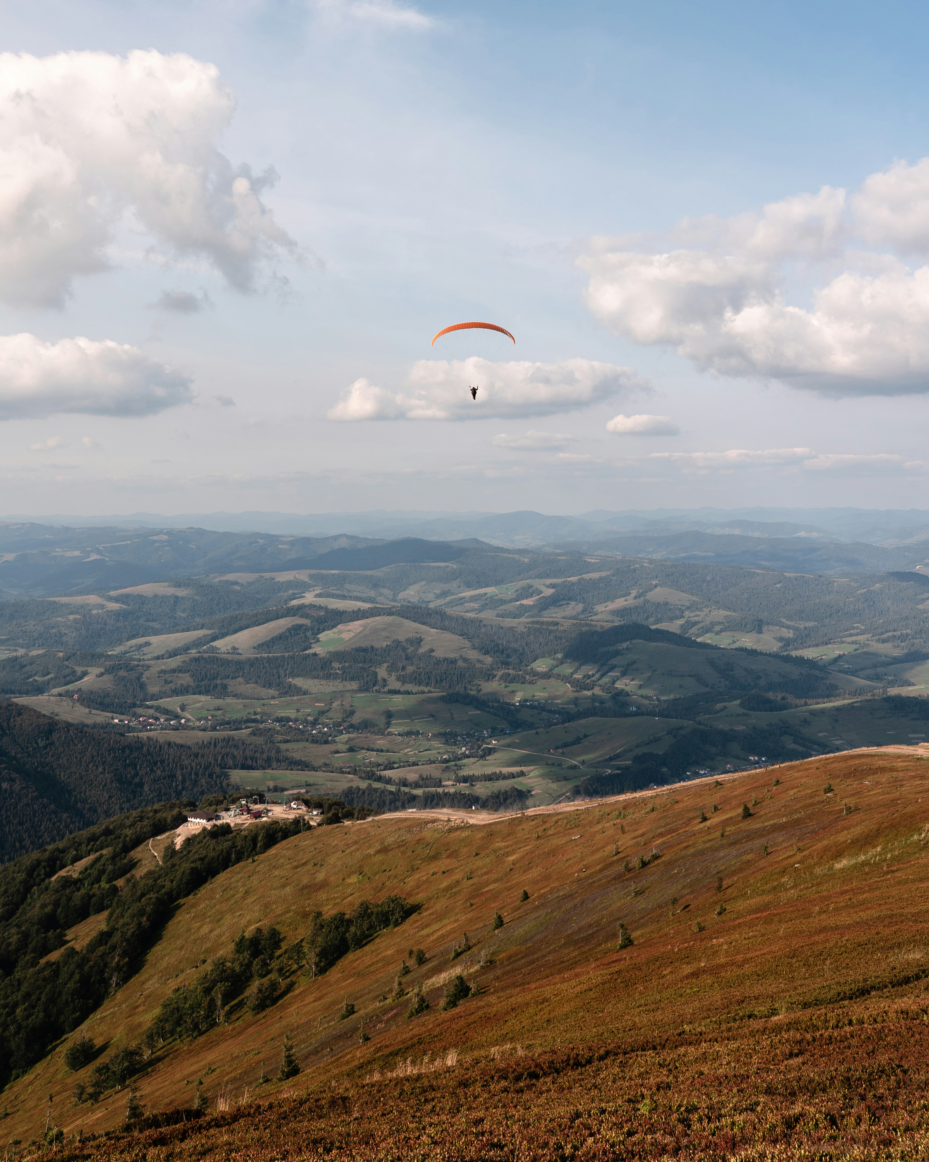 Glider Over Golden Ridges: Paraglider Tracing Quiet Currents Across Rolling Hills