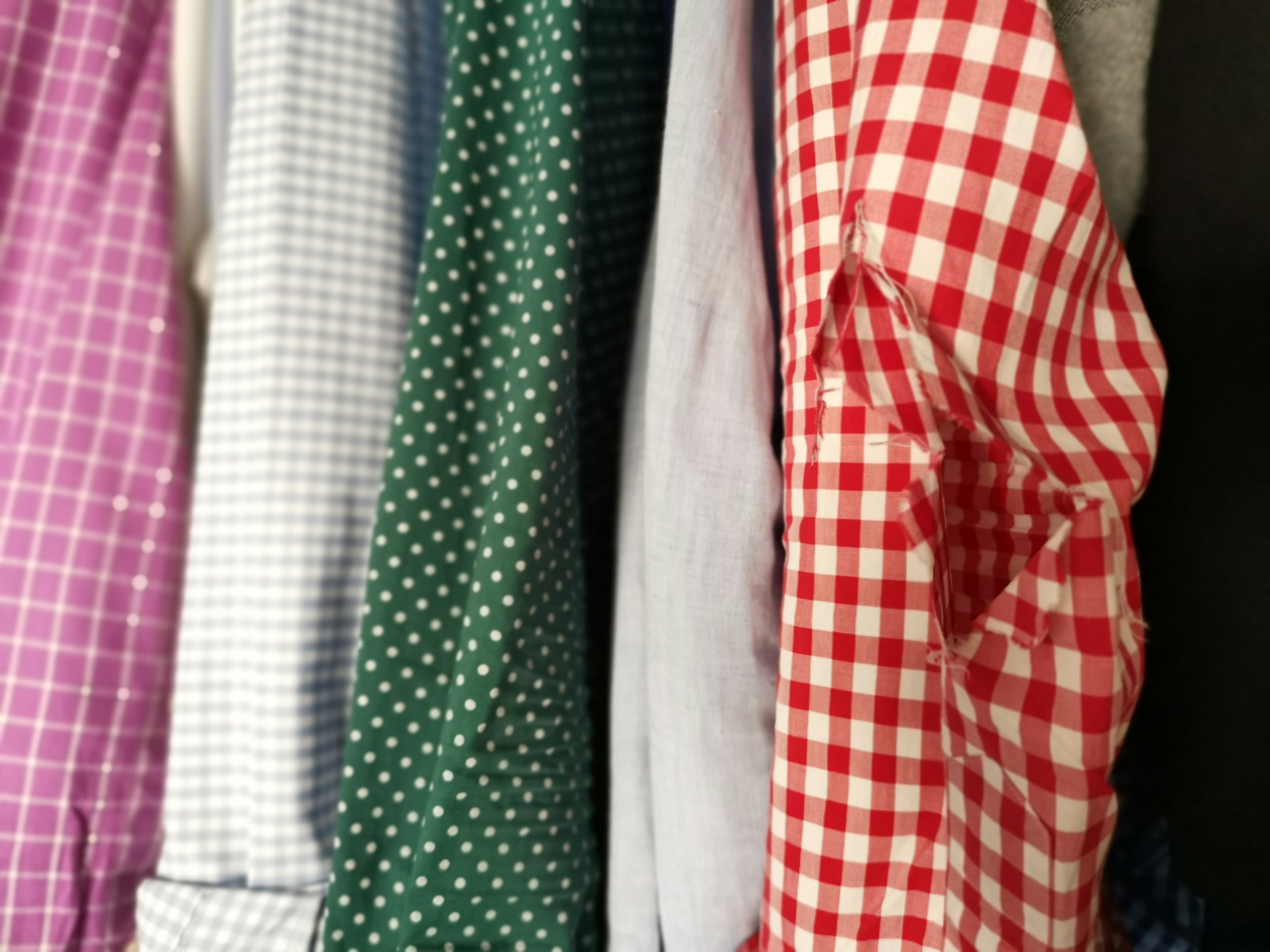 A collection of neatly hung shirts showcasing various patterns and colors, including checks and polka dots, highlighting textile diversity.
