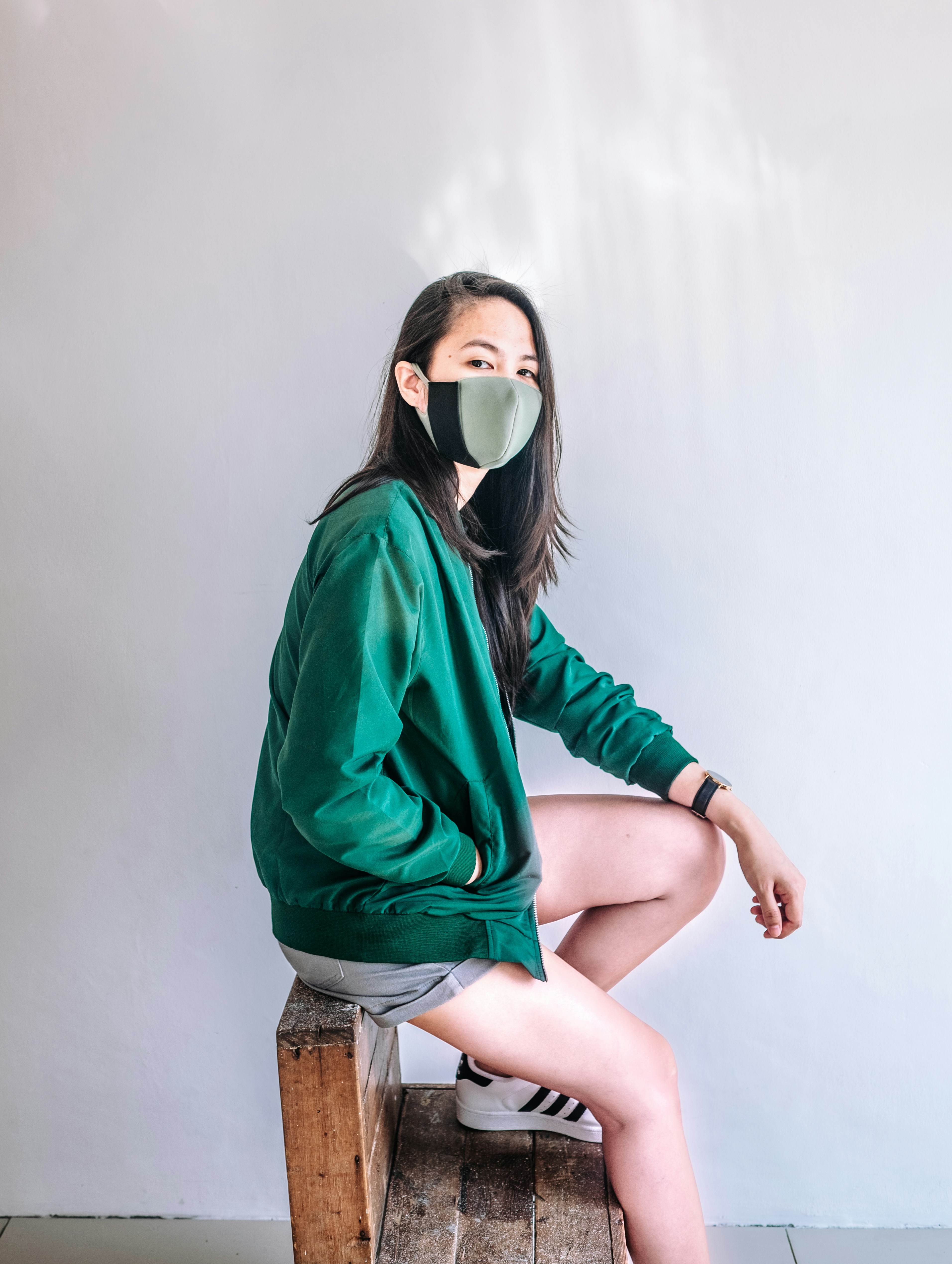 Muted Green, Quiet Gaze: A masked portrait on a wooden bench