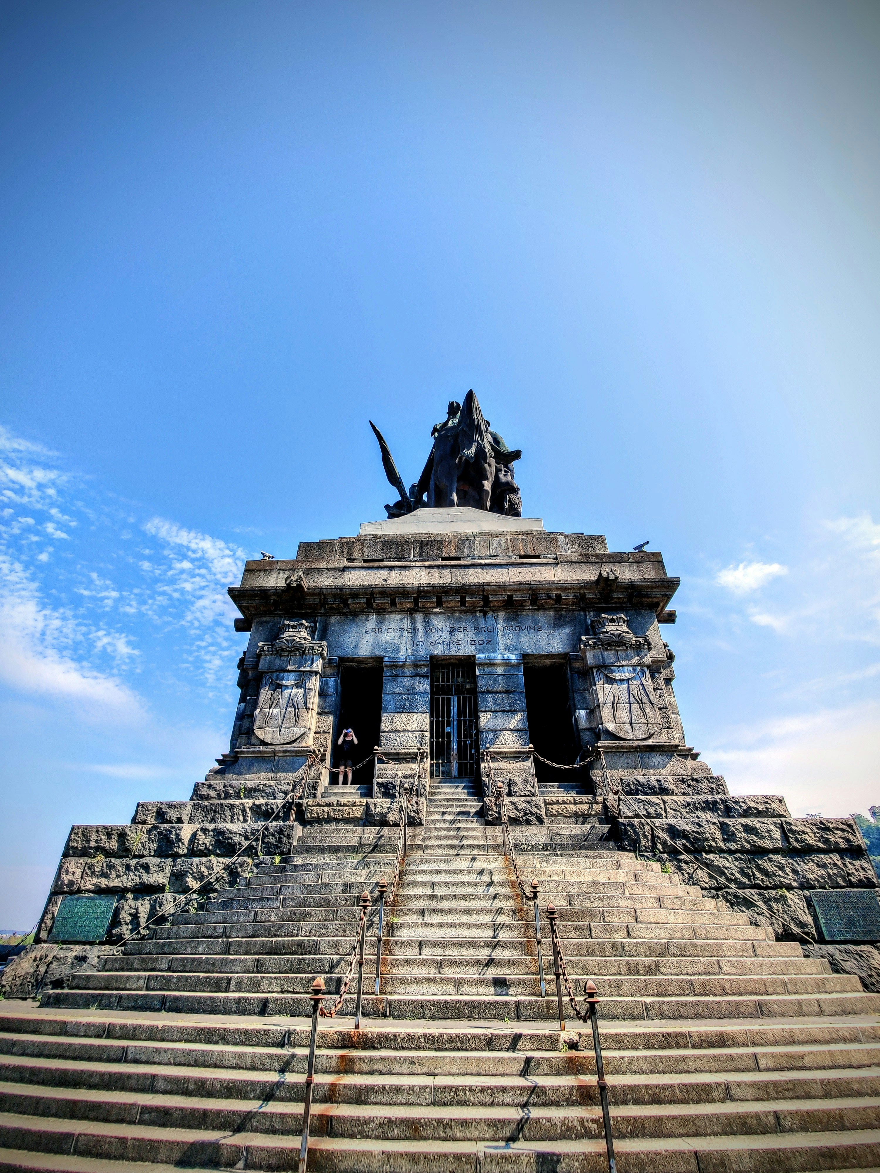 A view on the back of the Kaizer Wilhelm I monument, with steps leading up to the inner building from which tourists can view both rivers Mosel and Rhein. | black bird on top of gray concrete building