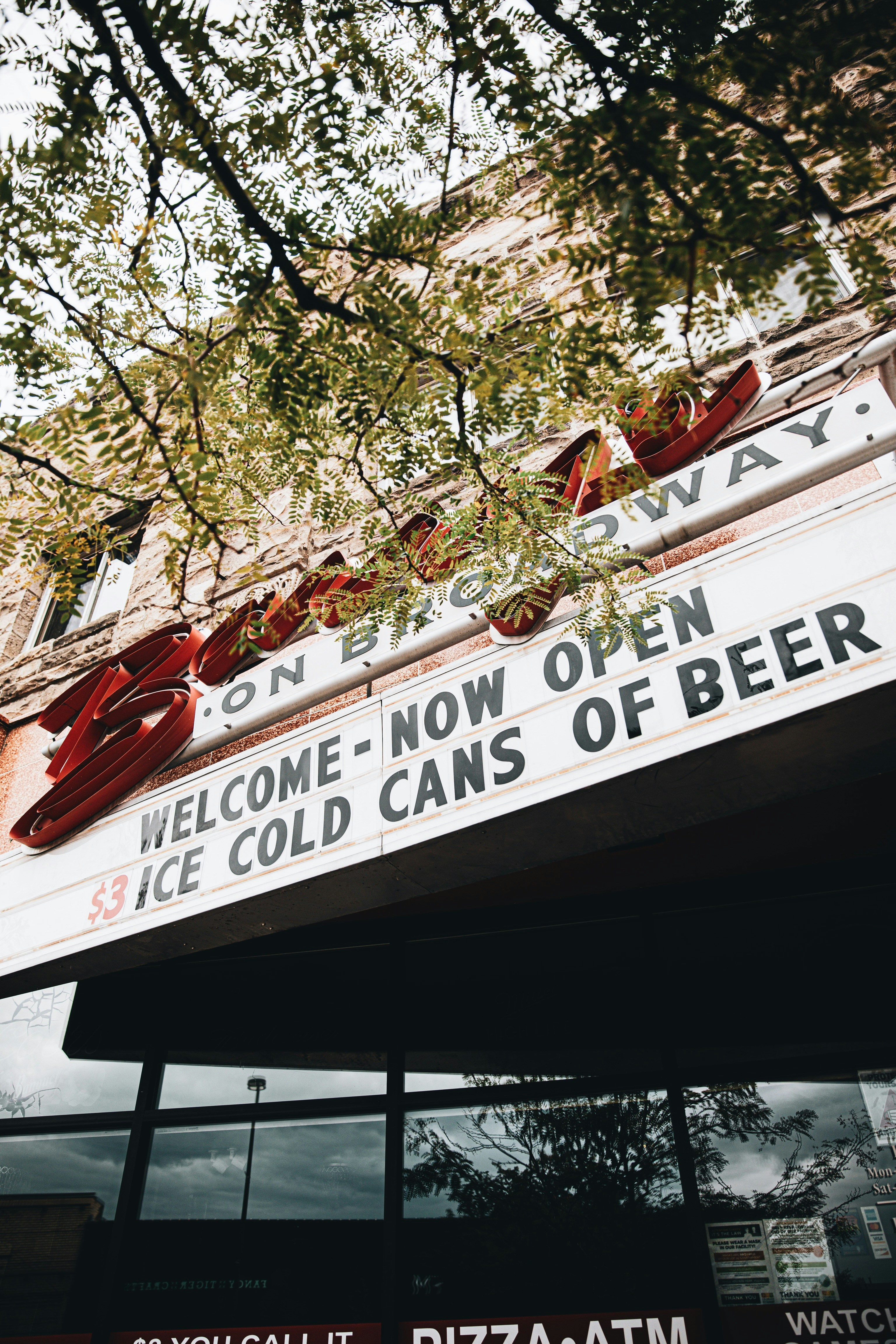 Tilted Marquee under a Leafy Canopy: A Vintage Theater Sign