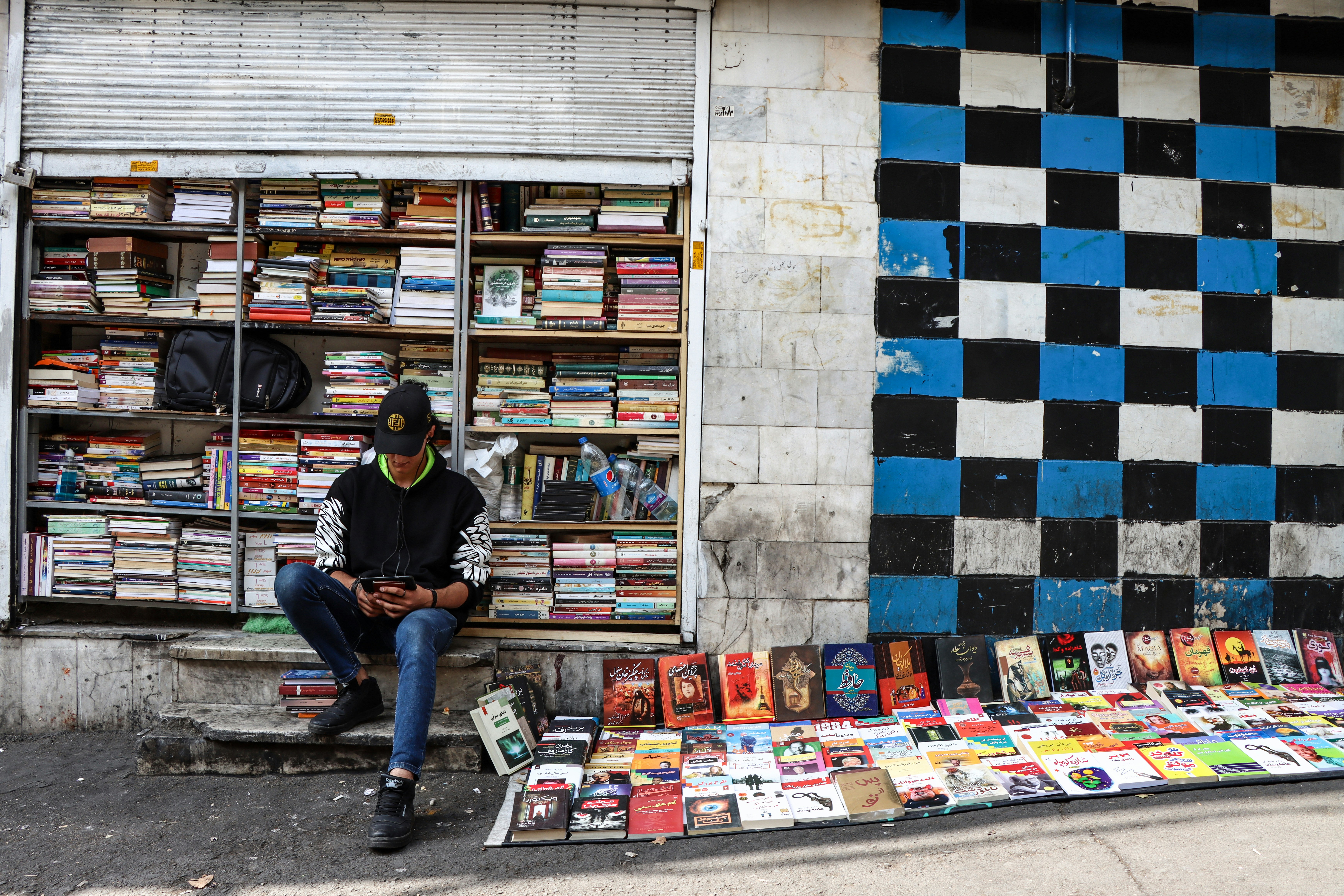 Sidewalk Bookseller Beneath a Checkerboard Façade