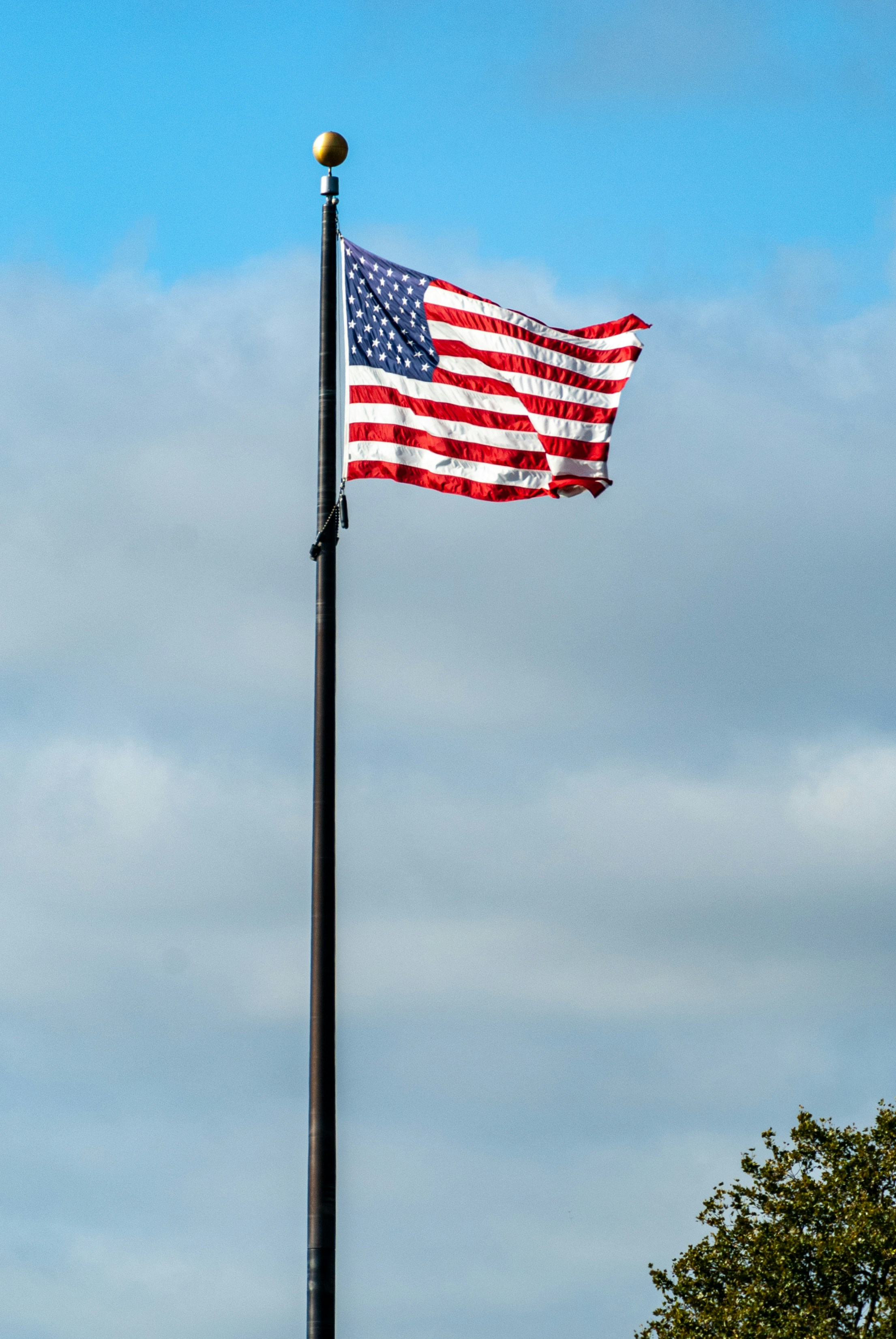 American flag waving proudly against a backdrop of blue skies and scattered clouds.