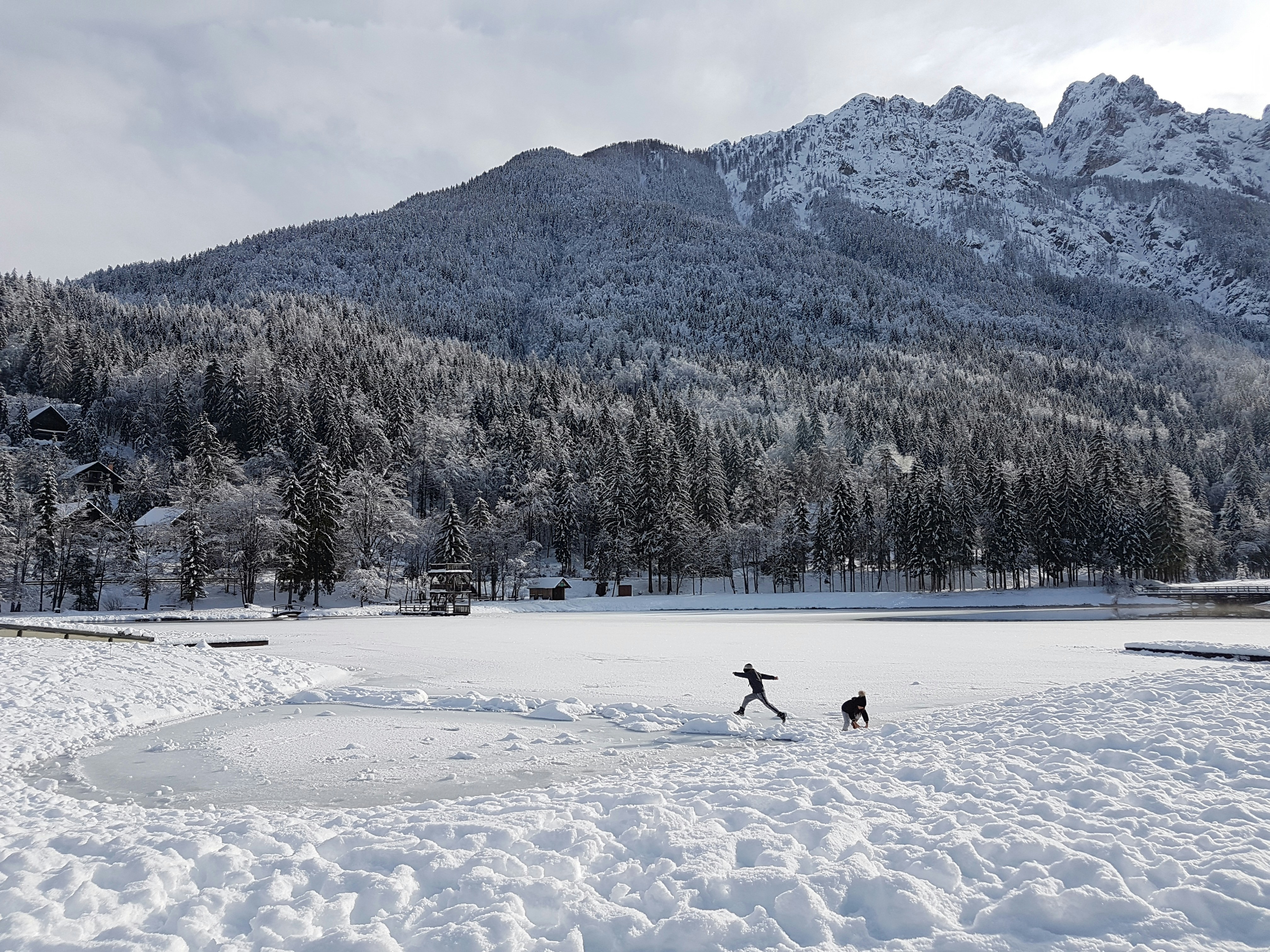 Frozen Lake Dance: Two Figures Skating on a Still Alpine Afternoon