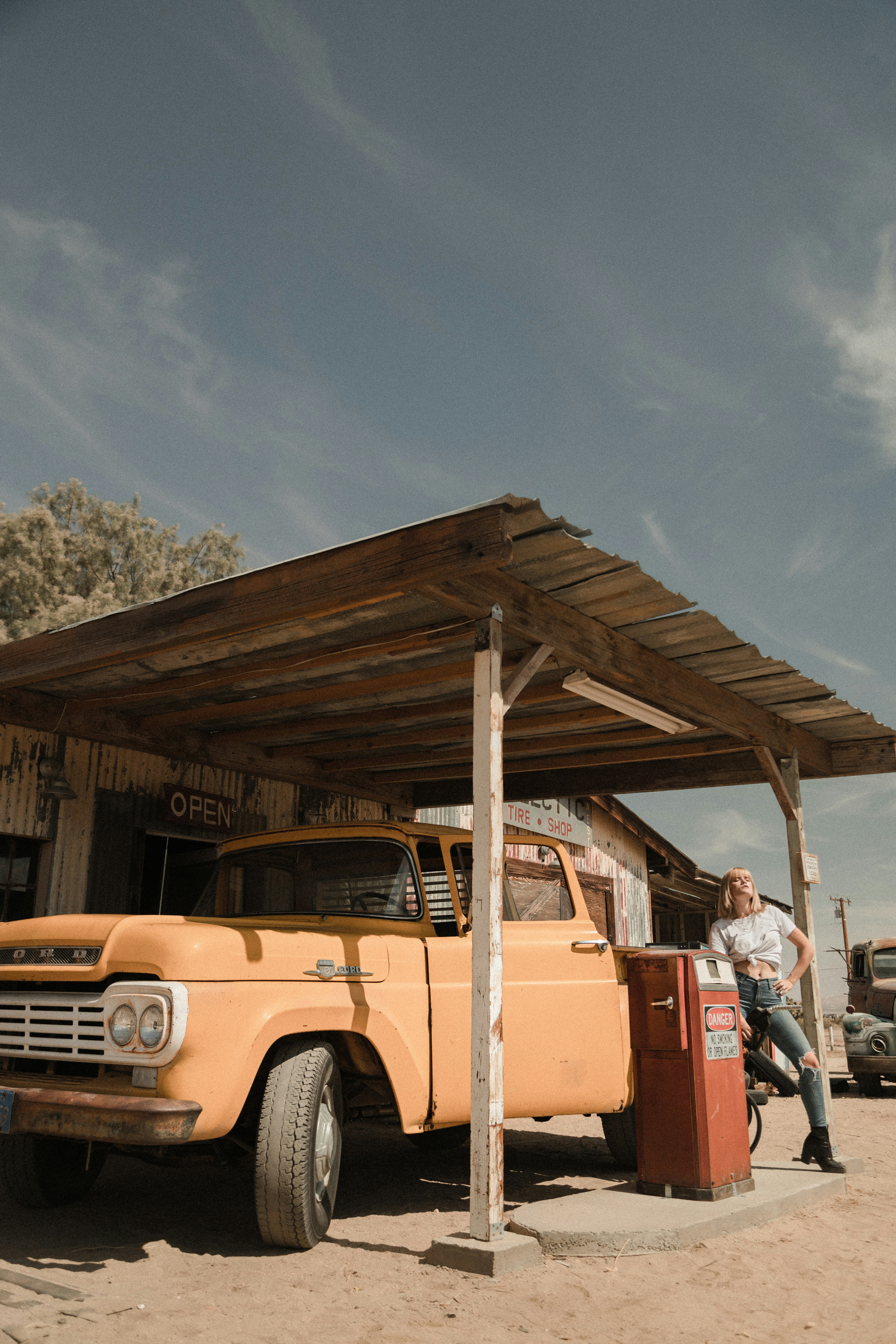 Sunlit Desert Salvage: A vintage yellow pickup at a weathered fuel stop
