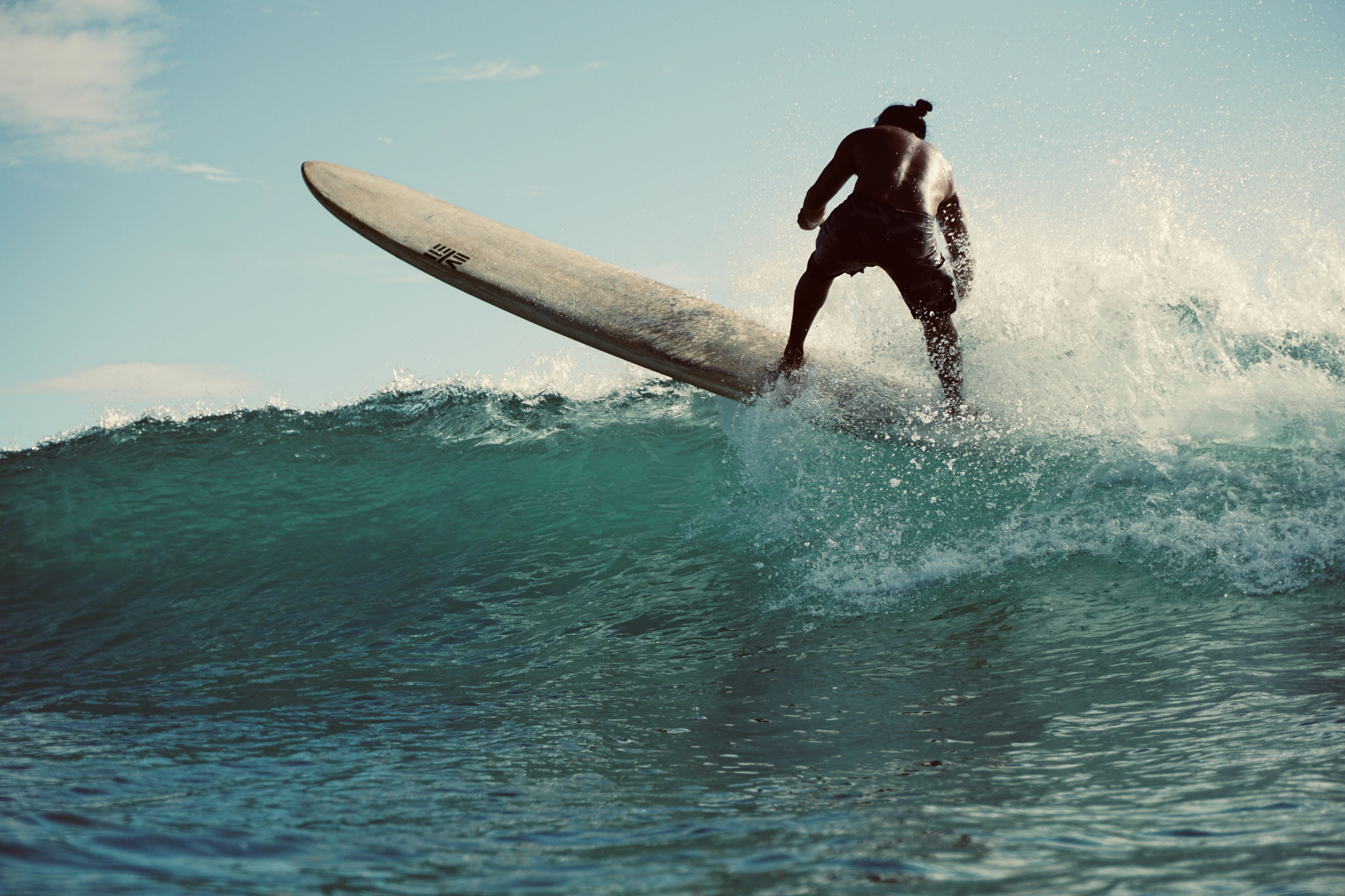 Surfer skillfully navigating a wave, showcasing the thrill of ocean sports amidst splashing water and sunlight.