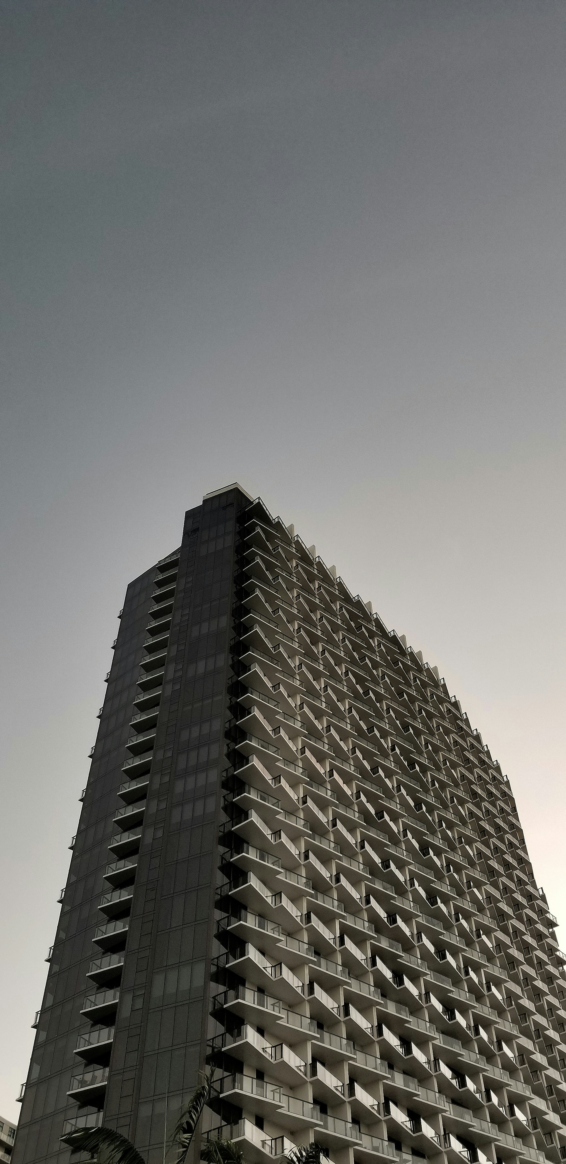 A high-rise building showcasing a unique facade with geometric balconies against a muted sky.
