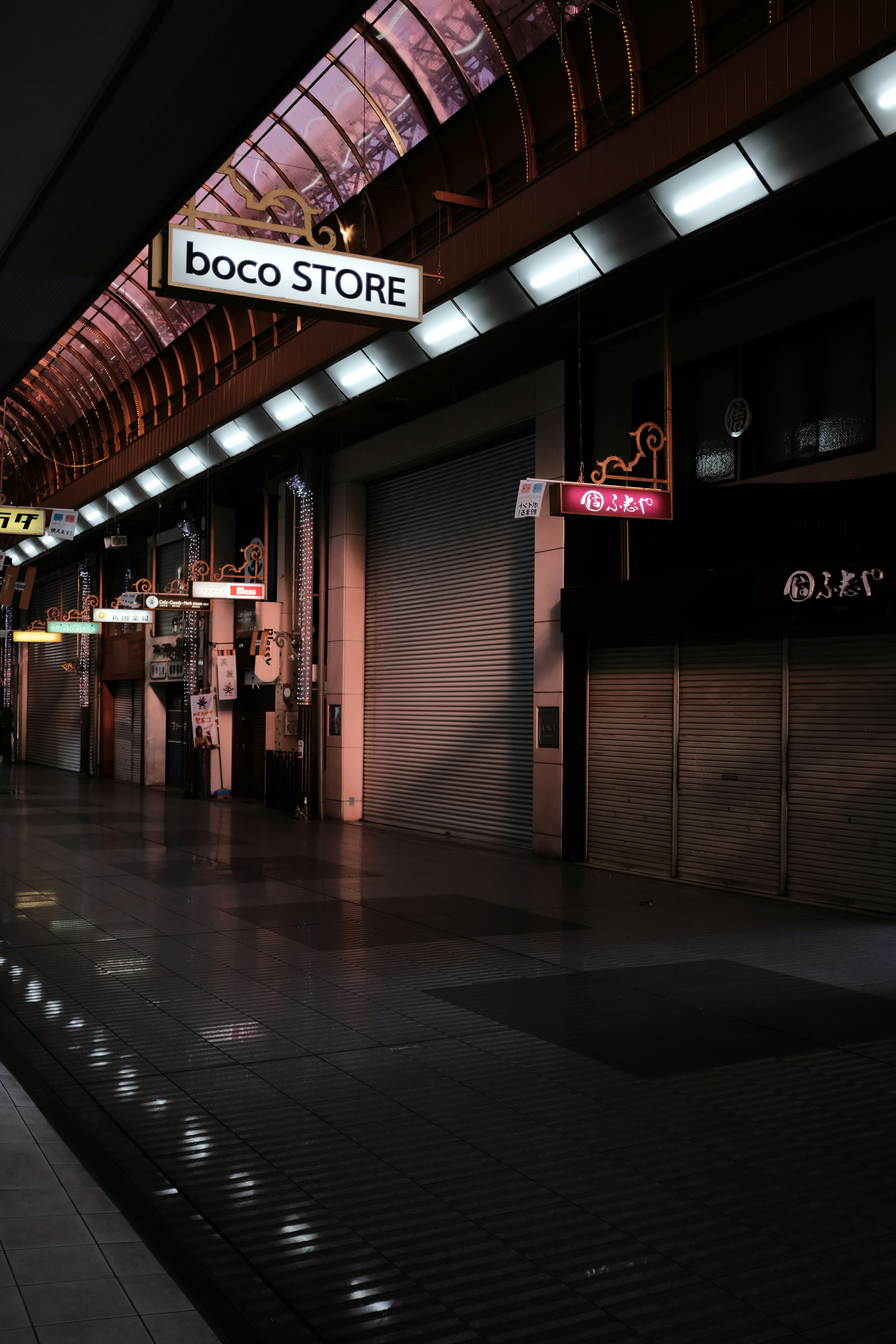 Abandoned storefronts line a dimly lit corridor, with the boco STORE sign prominently displayed above. The atmosphere reflects a stillness, capturing the essence of a once-bustling marketplace.