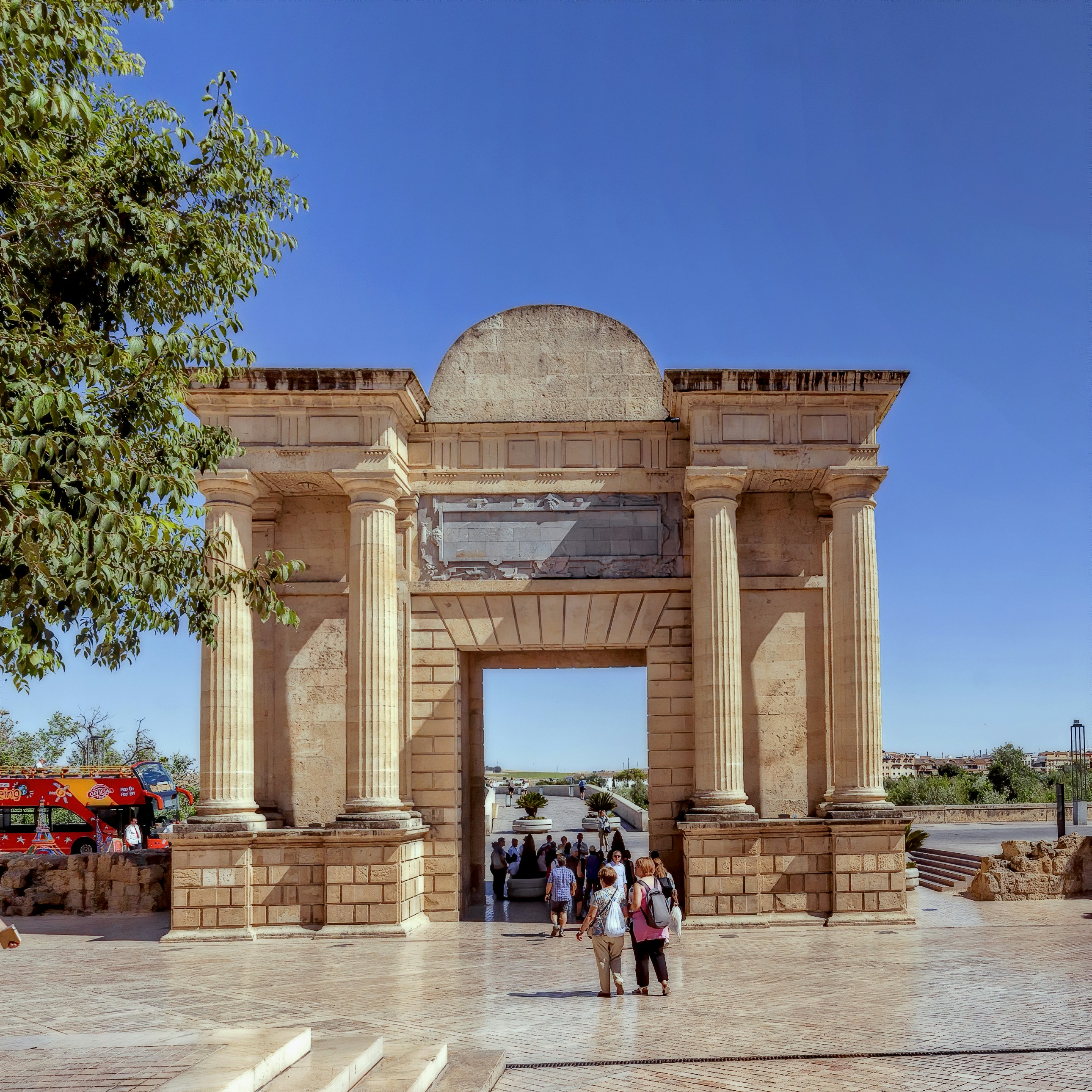 Architectural arch framed by lush greenery, inviting visitors to explore the historical site beyond.