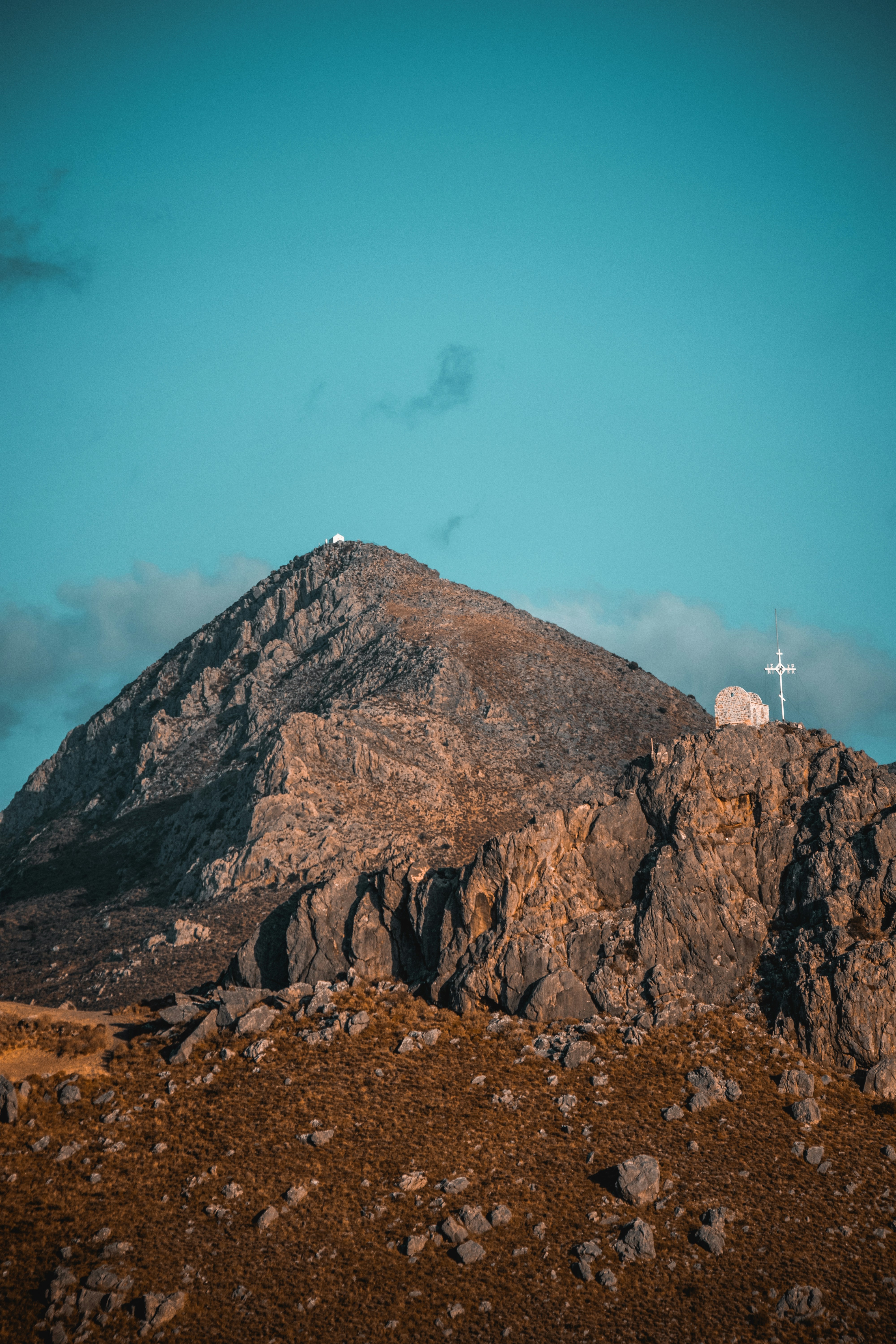 Cross on the Crest: A Rugged Peak Beneath a Turquoise Sky