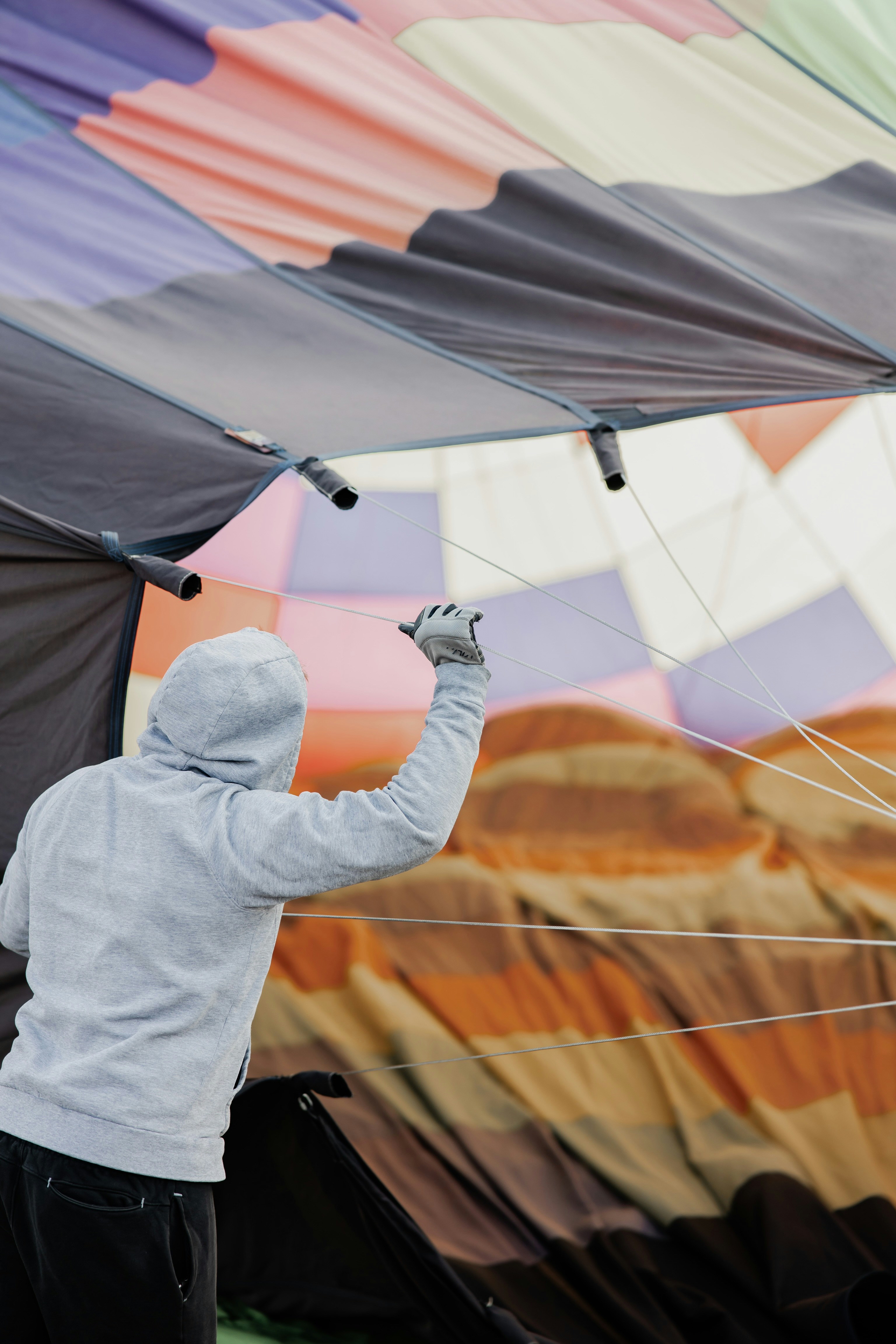 Inflating the Sky: A climber tugs at a rainbow-canvas hot air balloon