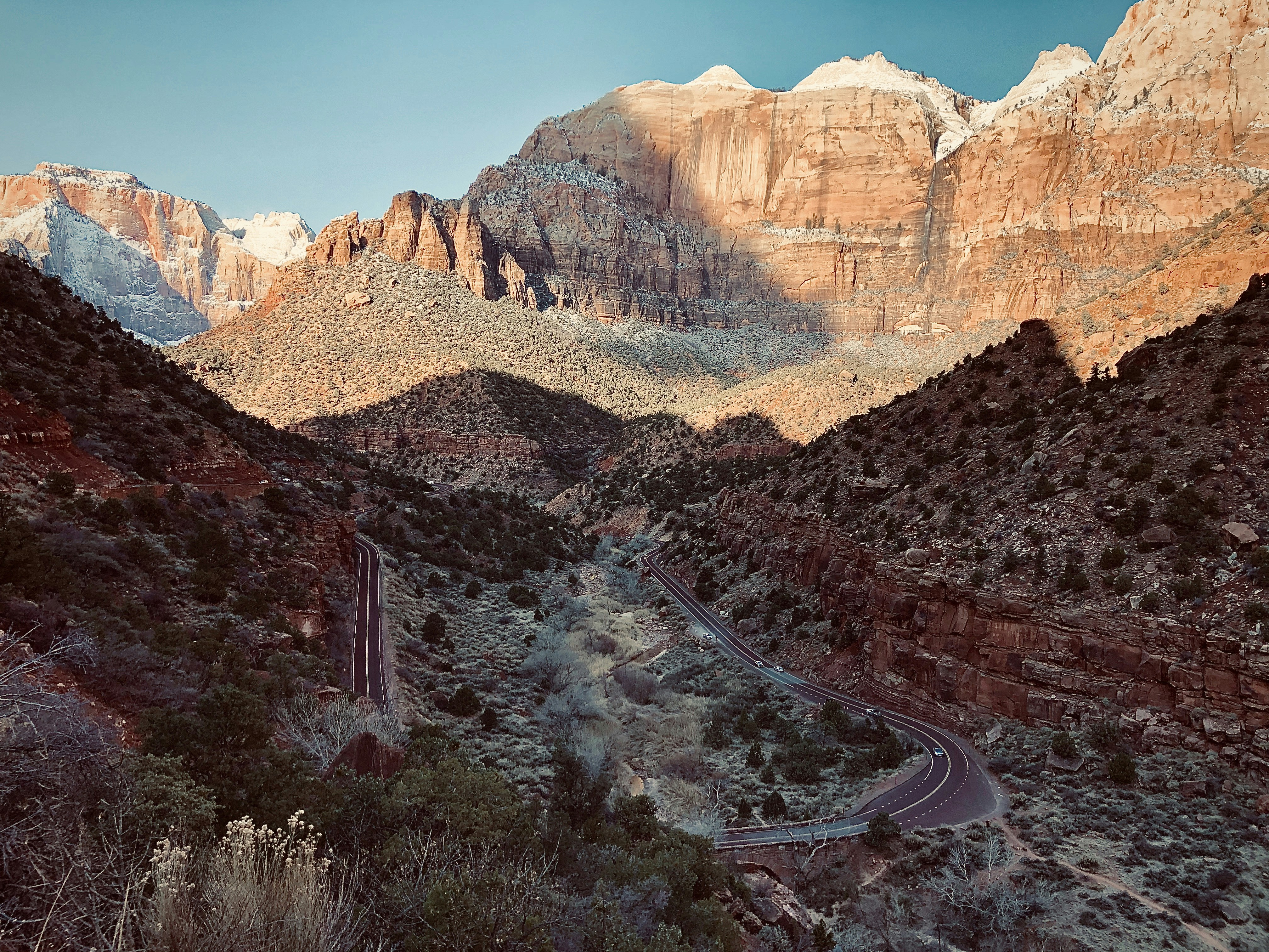 Winding road through a rugged mountain landscape under a clear blue sky.
