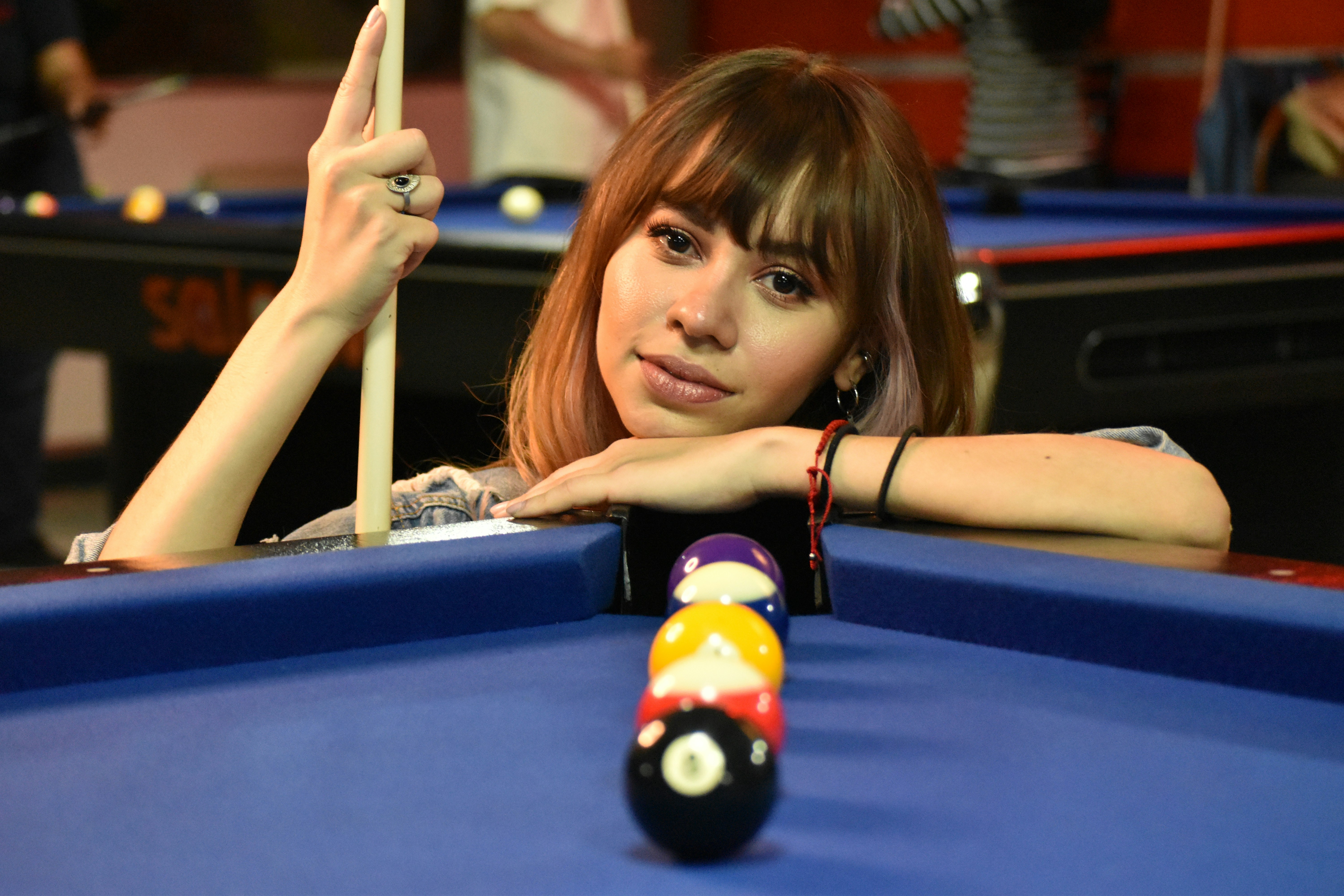 girl in black and red striped shirt playing billiard