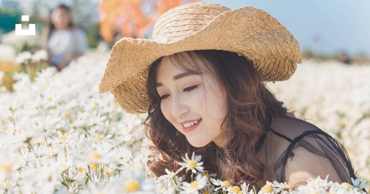 낮에 흰 꽃 옆에 서 있는 갈색 태양 모자를 쓴 여자 사진 Unsplash의 무료 소녀 이미지